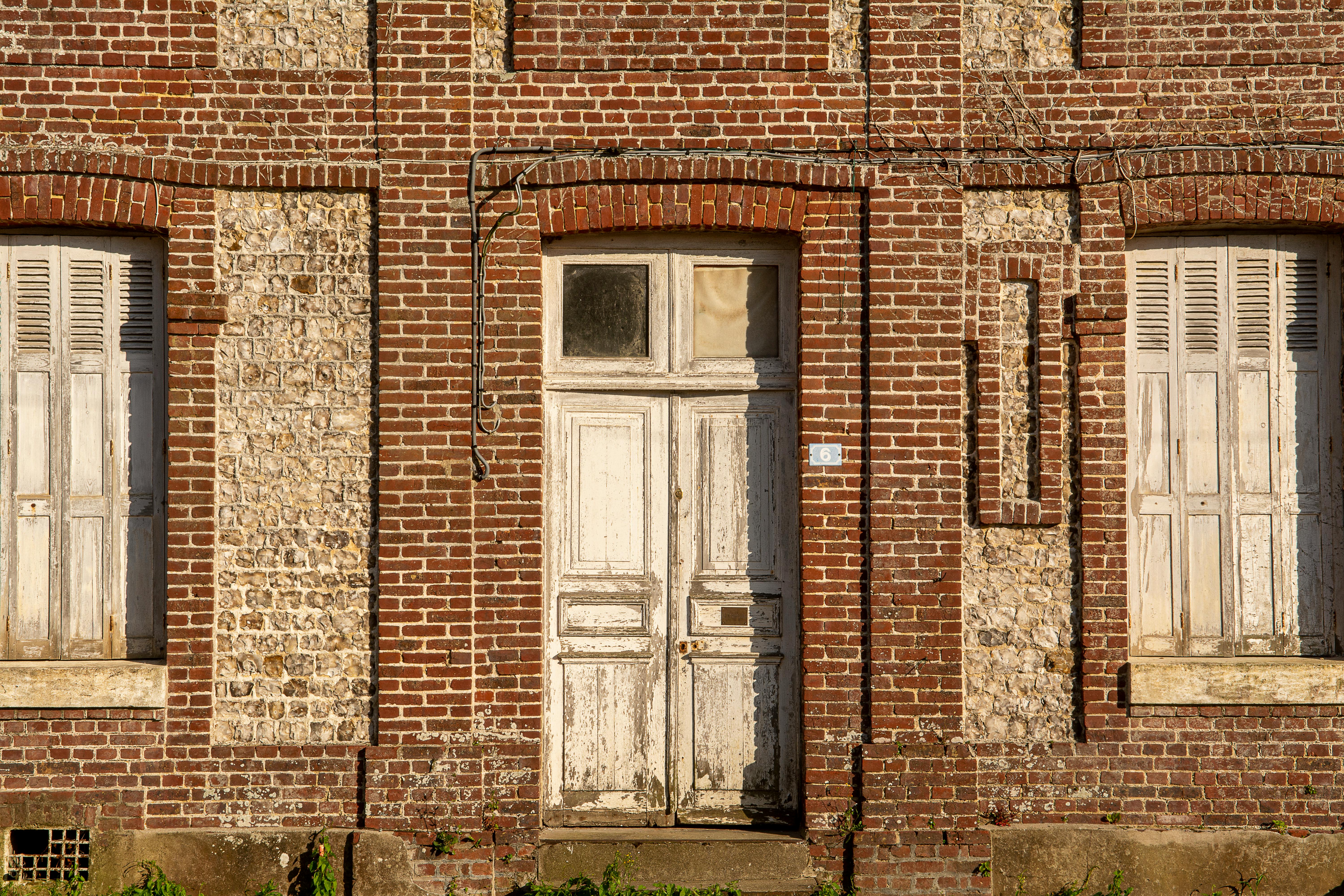 Rustic Brick and Stone Facade with Worn Doors · Free Stock Photo