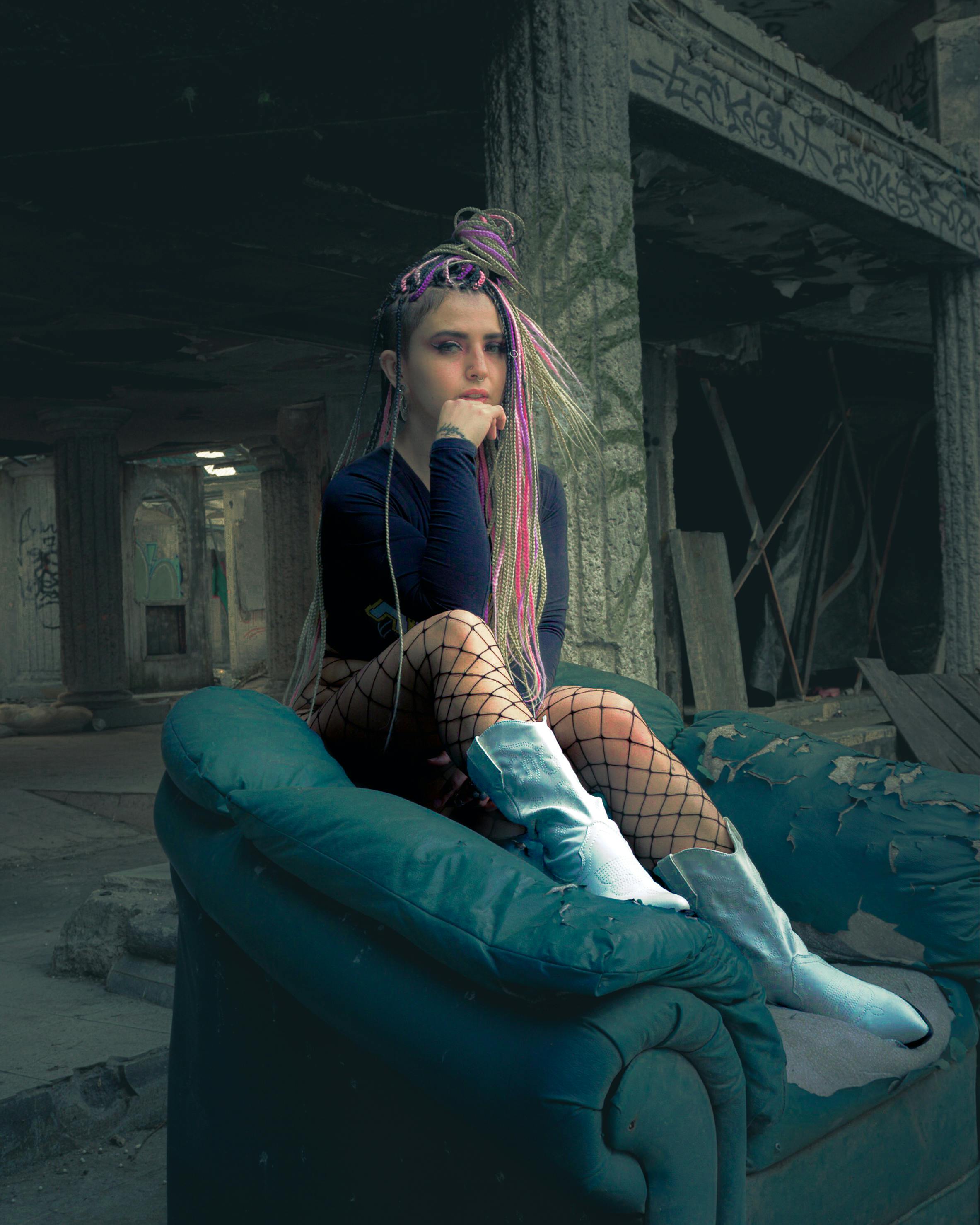 Edgy Woman Sitting on Blue Sofa in Urban Setting · Free Stock Photo