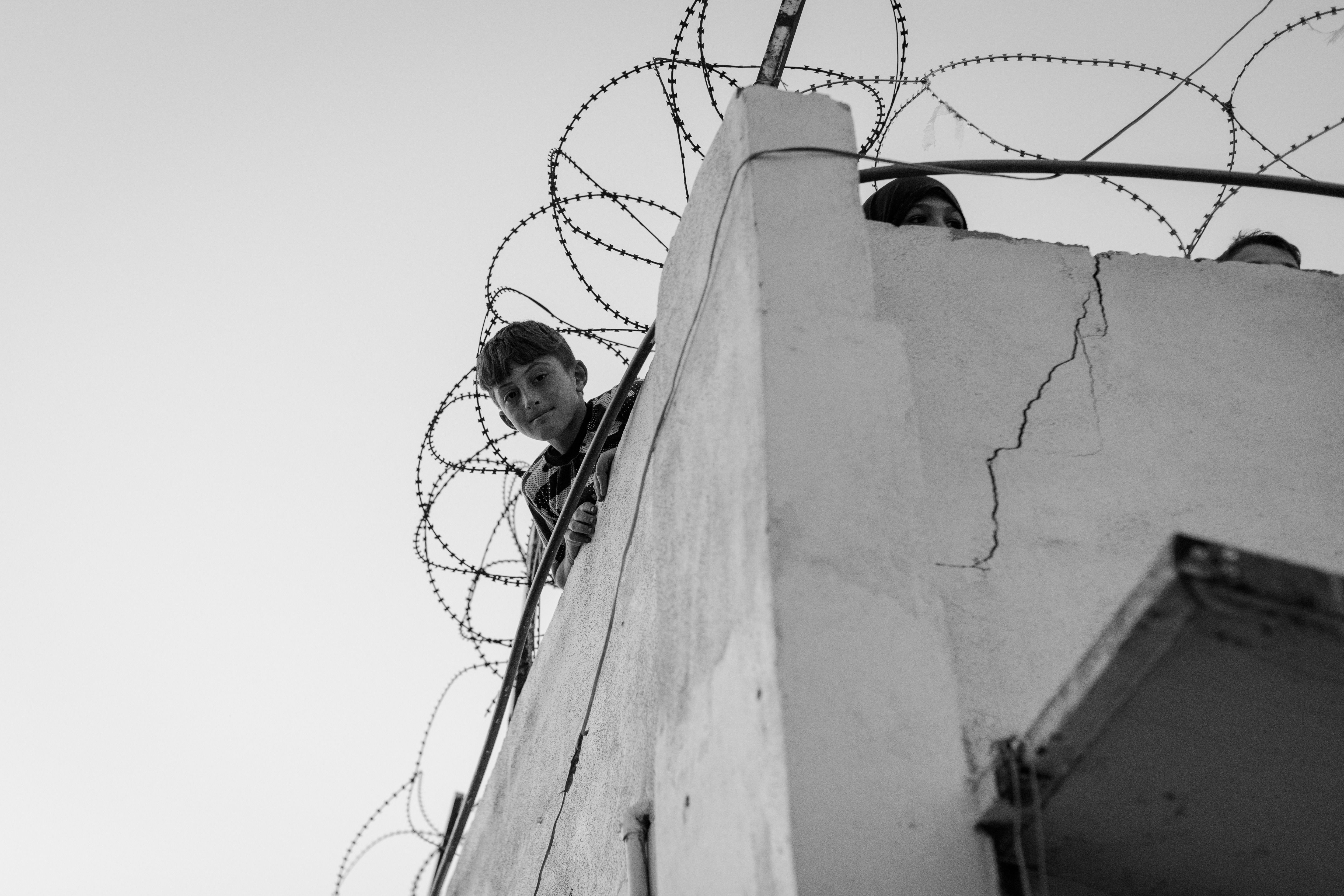 Child Observing from a Barbed-Wire Balcony in Lebanon · Free Stock Photo
