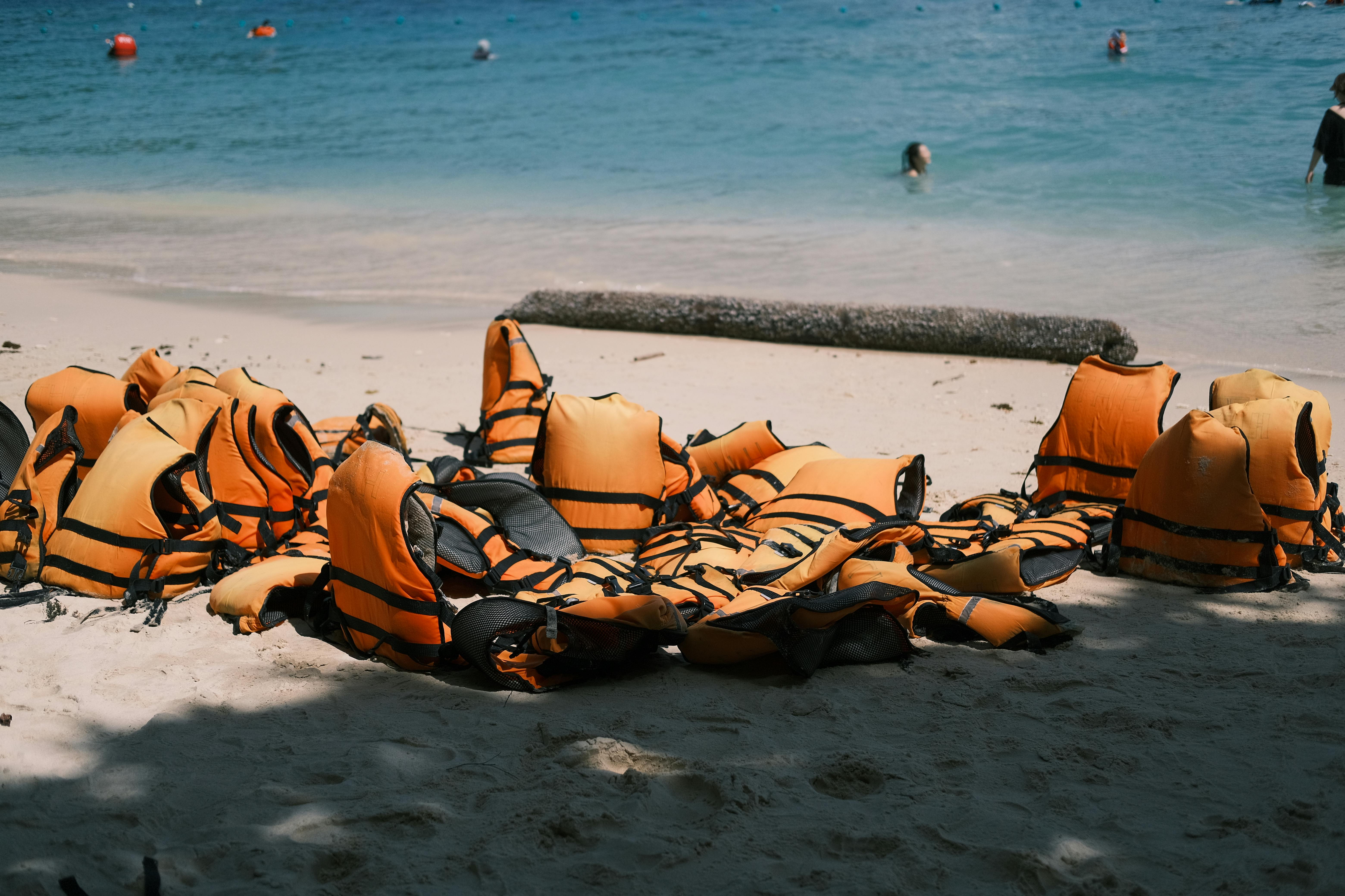Scattered life jackets on a sunny beach · Free Stock Photo