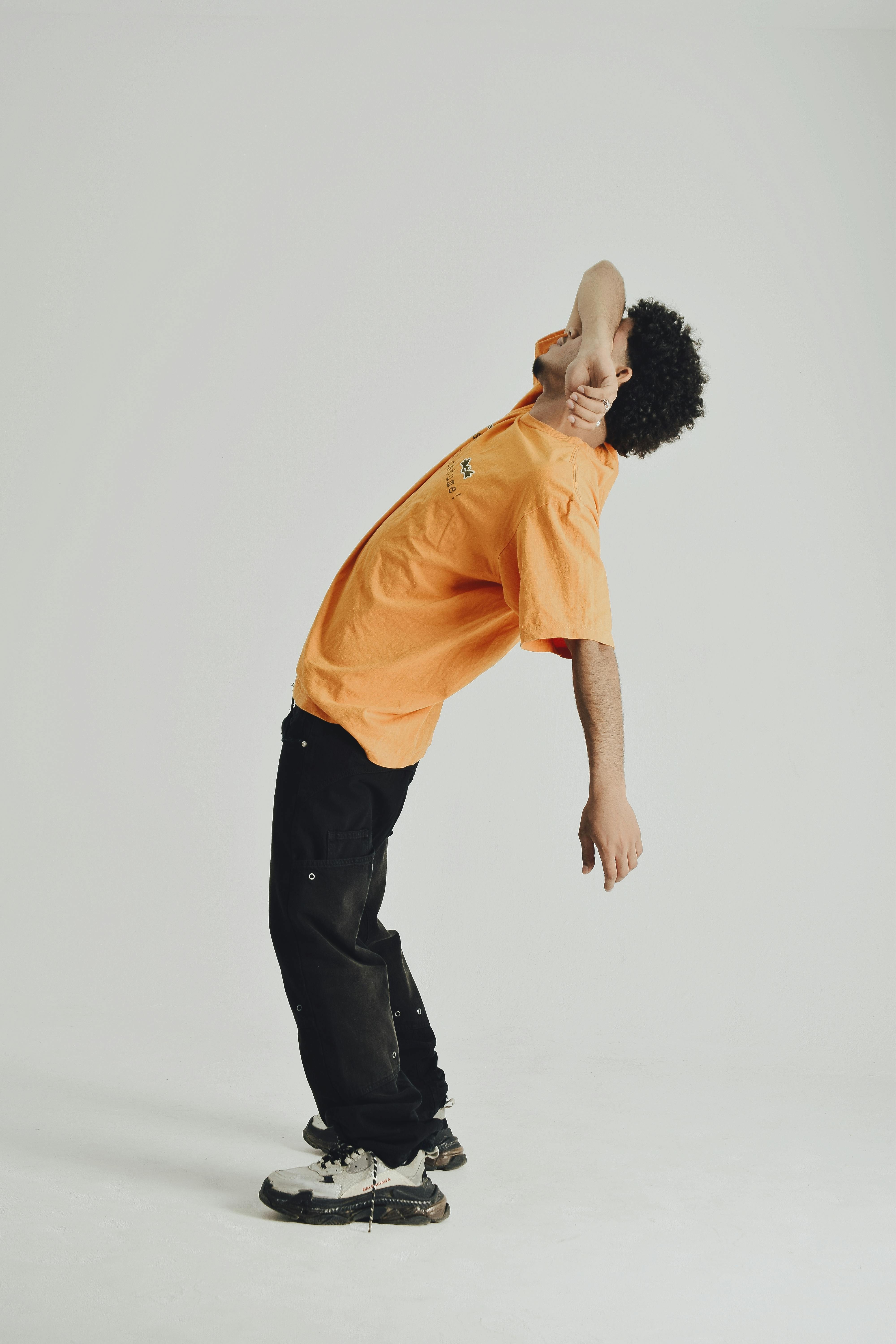 Expressive Male Model in Orange Shirt Studio Pose · Free Stock Photo