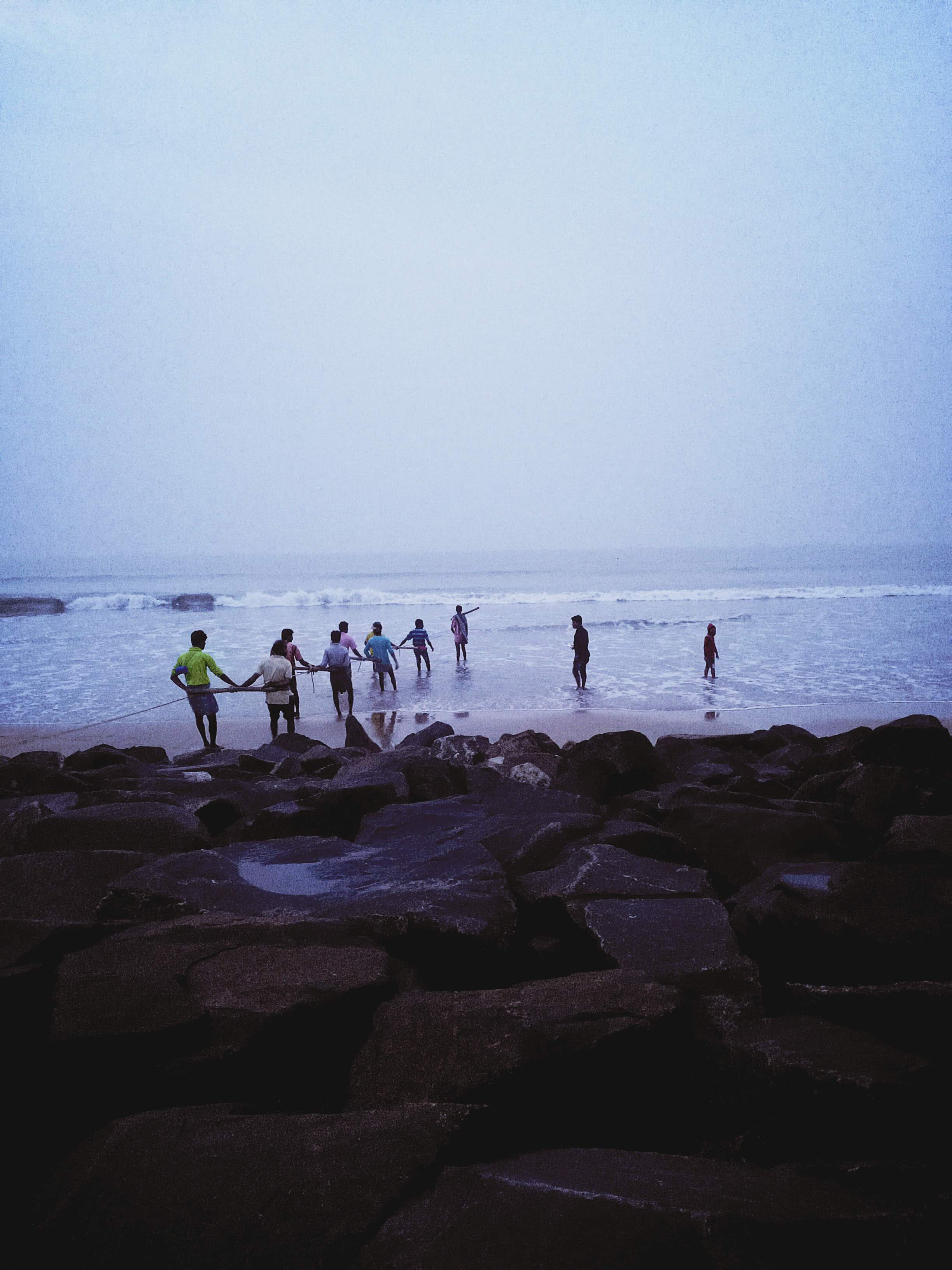 Early Morning Fishermen at Rocky Shoreline · Free Stock Photo