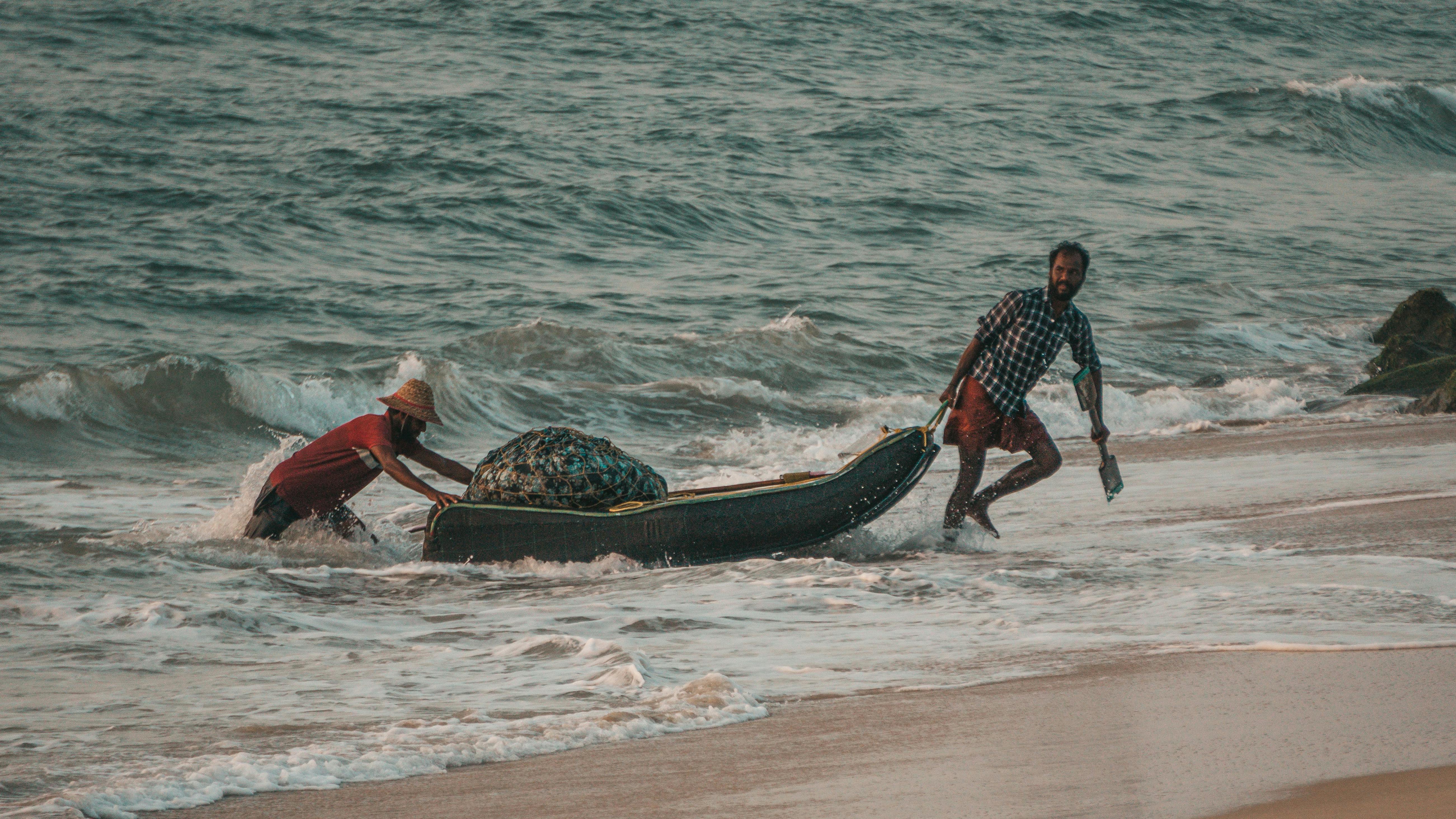 Fishermen Pulling Boat Ashore on Beach · Free Stock Photo