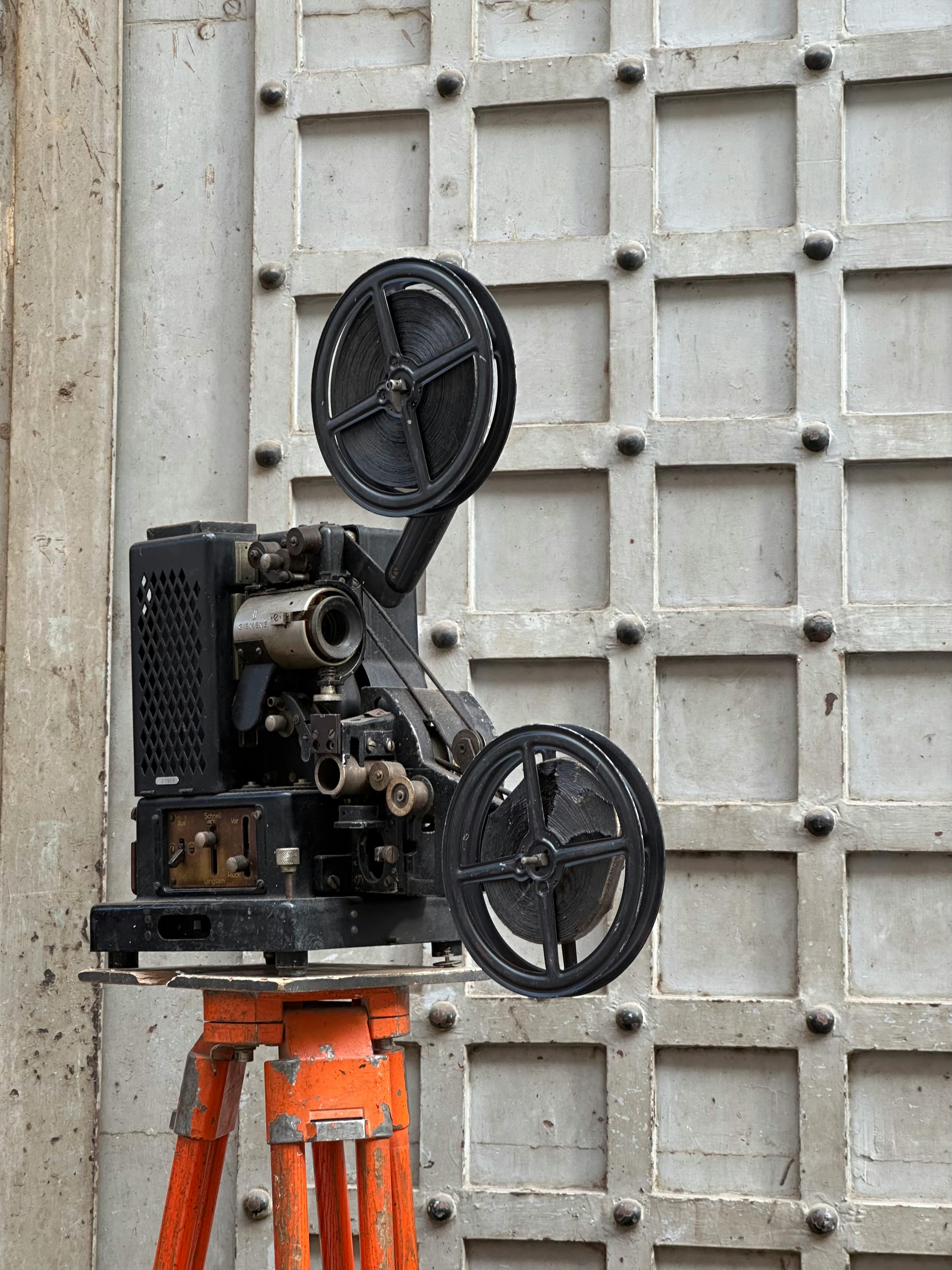 Vintage Film Projector on Stand Against Textured Wall · Free Stock Photo
