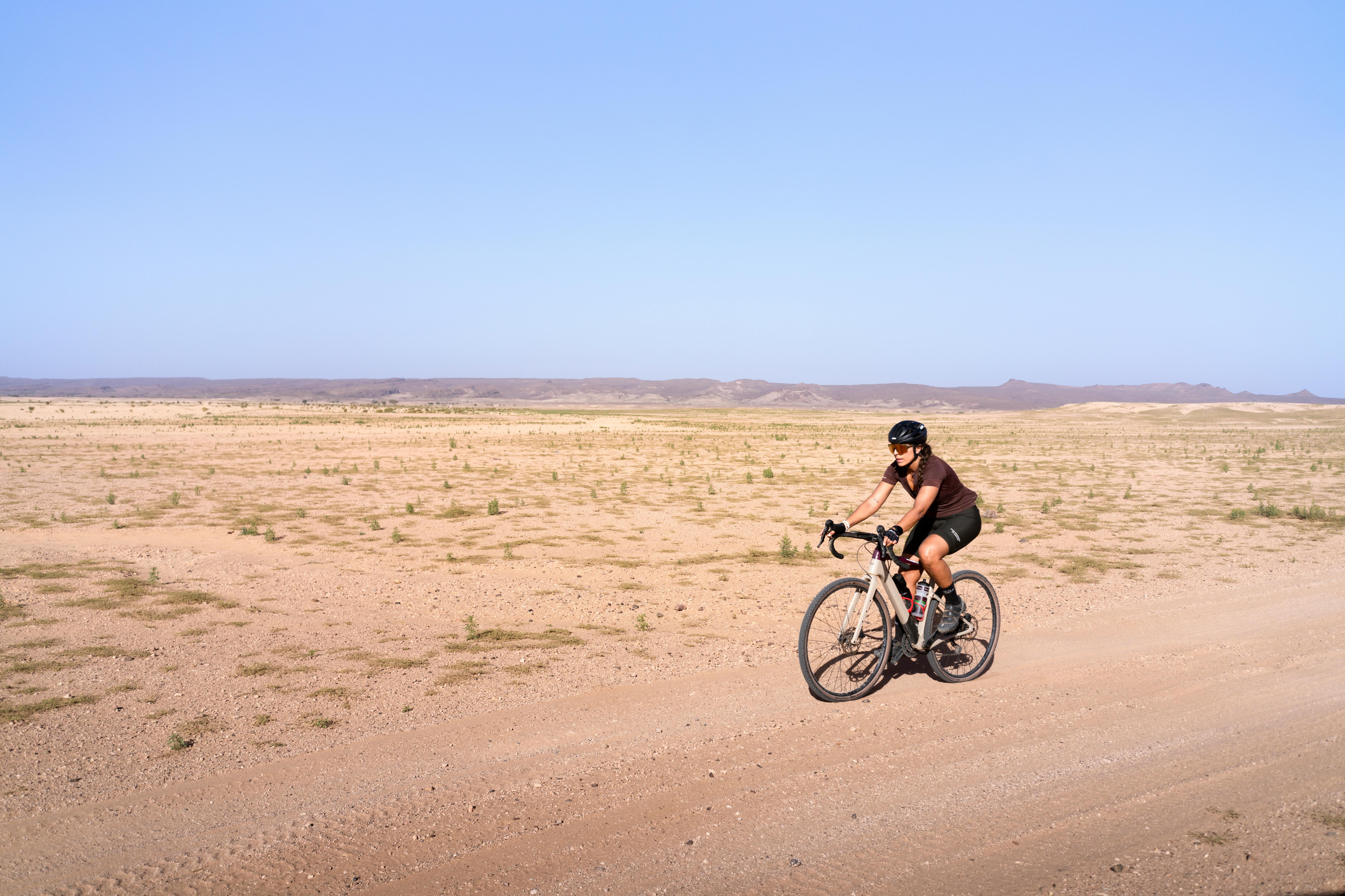 Cyclist Riding Through Vast Desert Landscape · Free Stock Photo