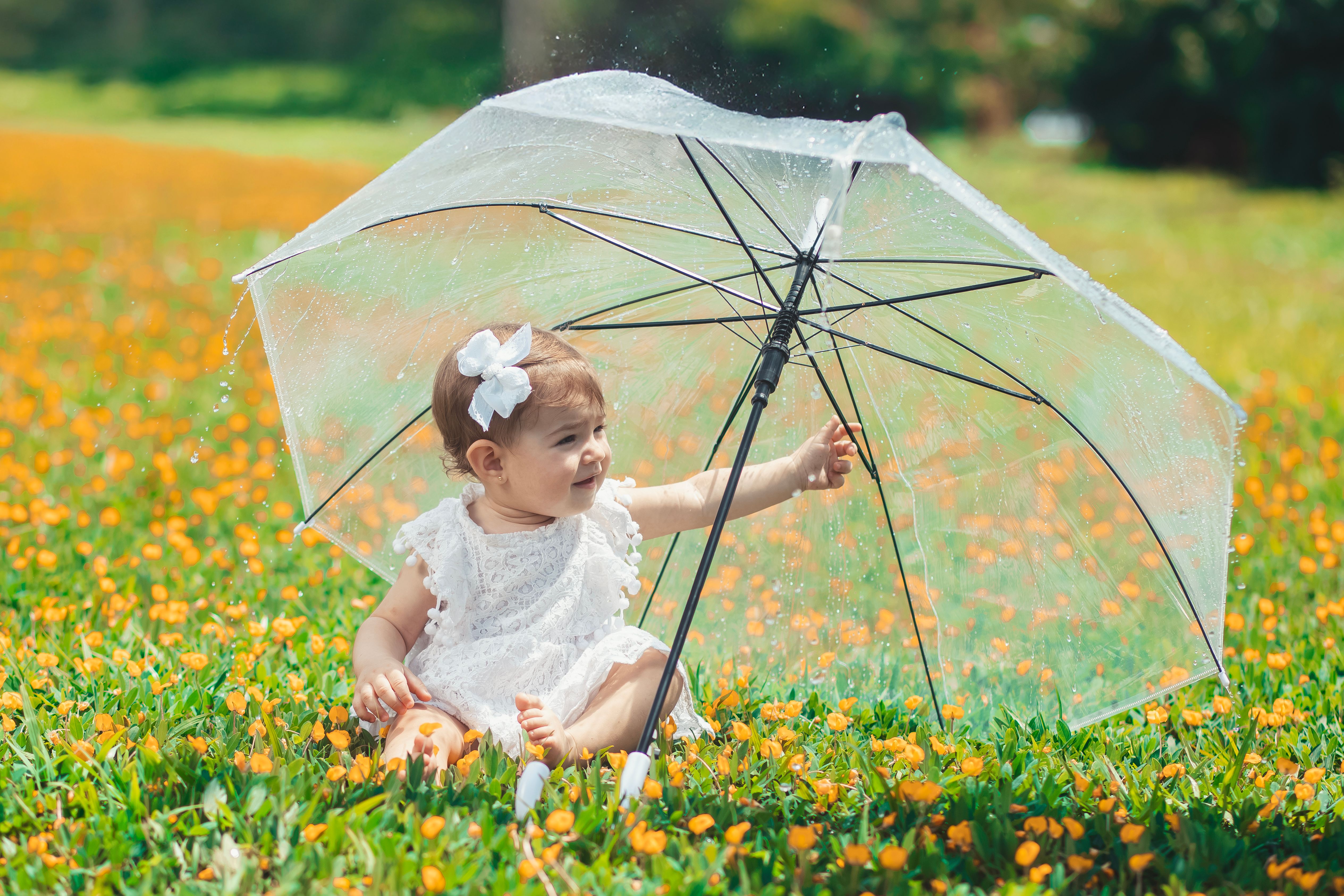 Adorable Baby with Umbrella in Blooming Field · Free Stock Photo