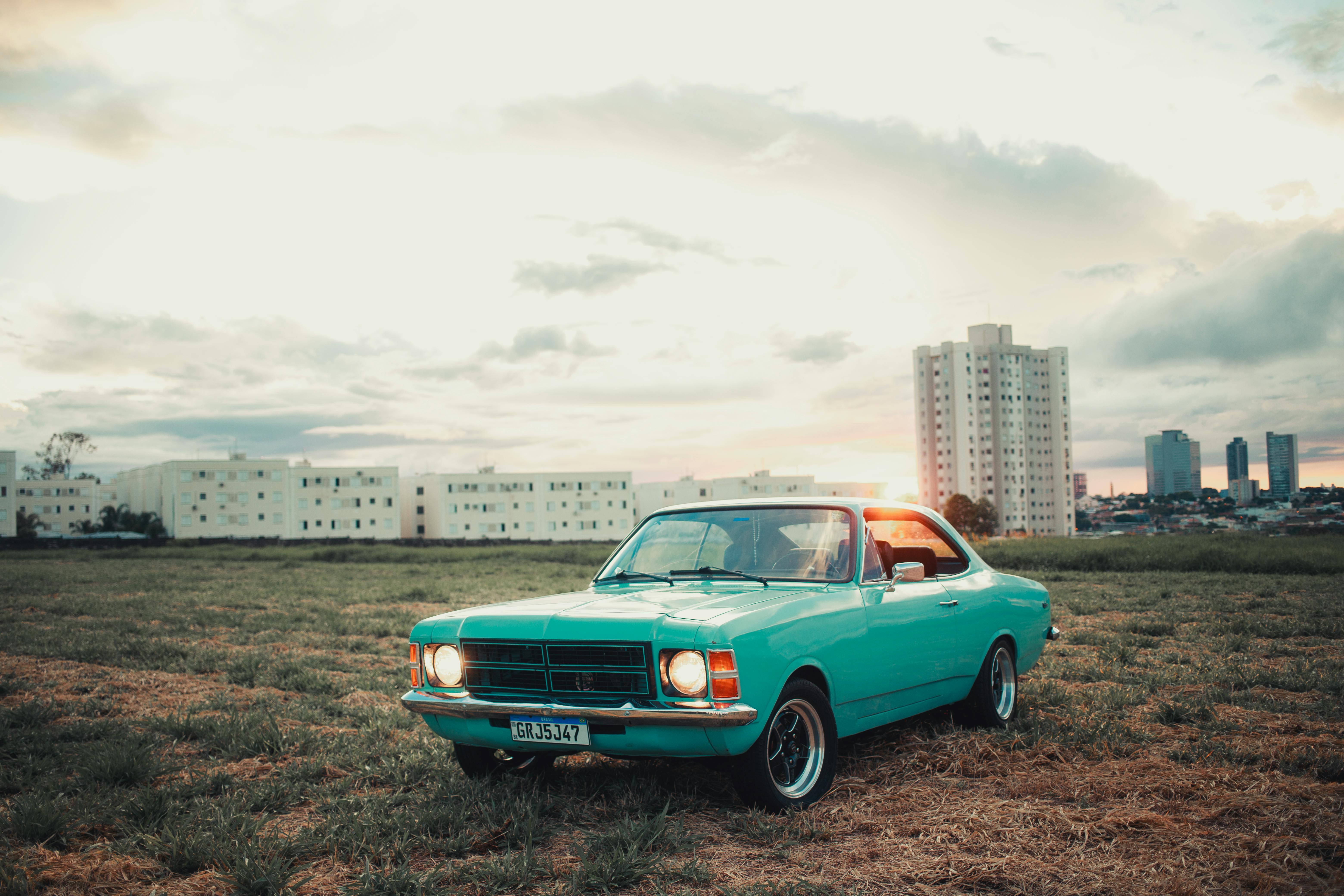 Classic turquoise car in urban sunset landscape · Free Stock Photo