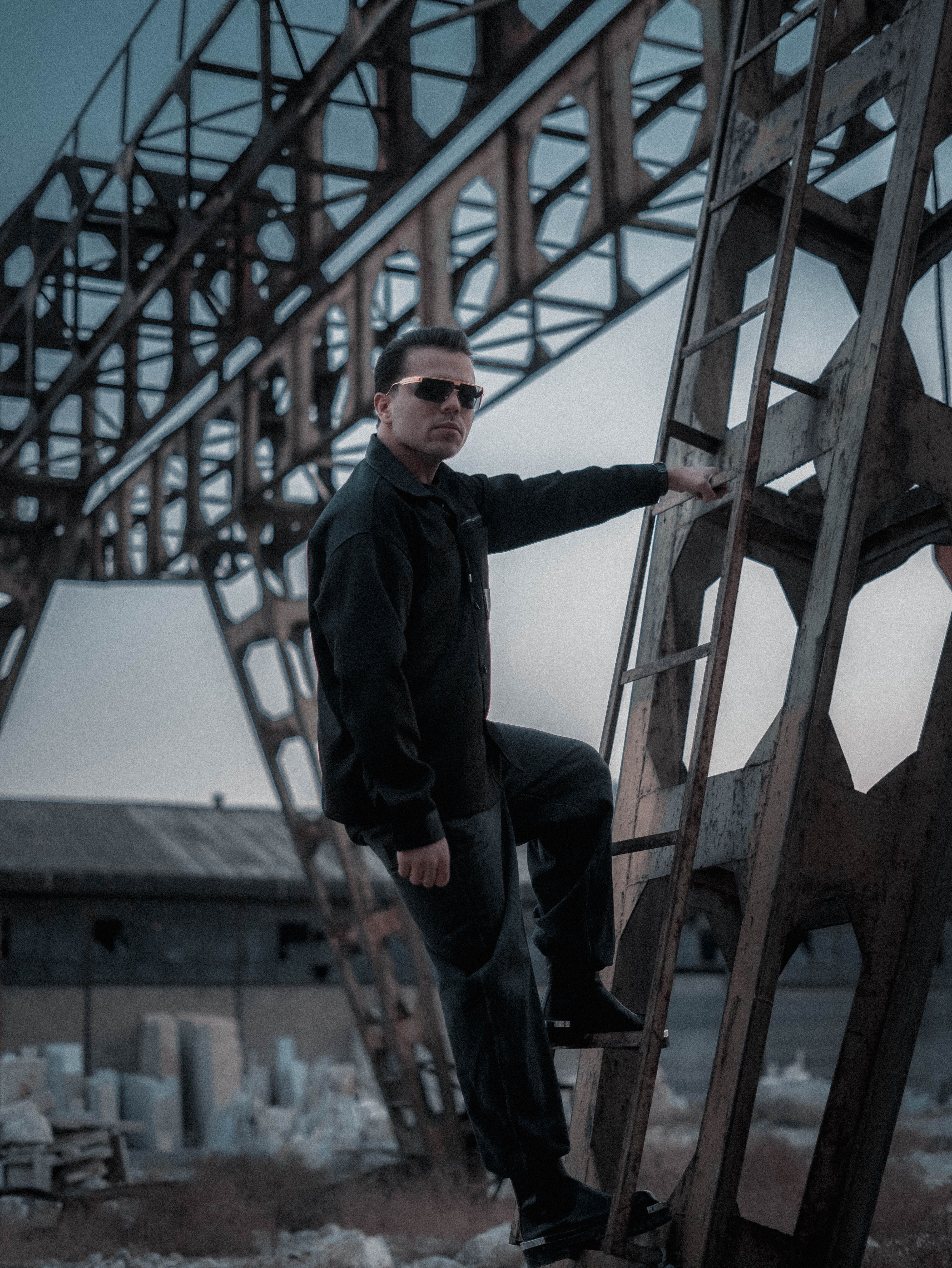 Man Climbing Industrial Structure at Dusk · Free Stock Photo