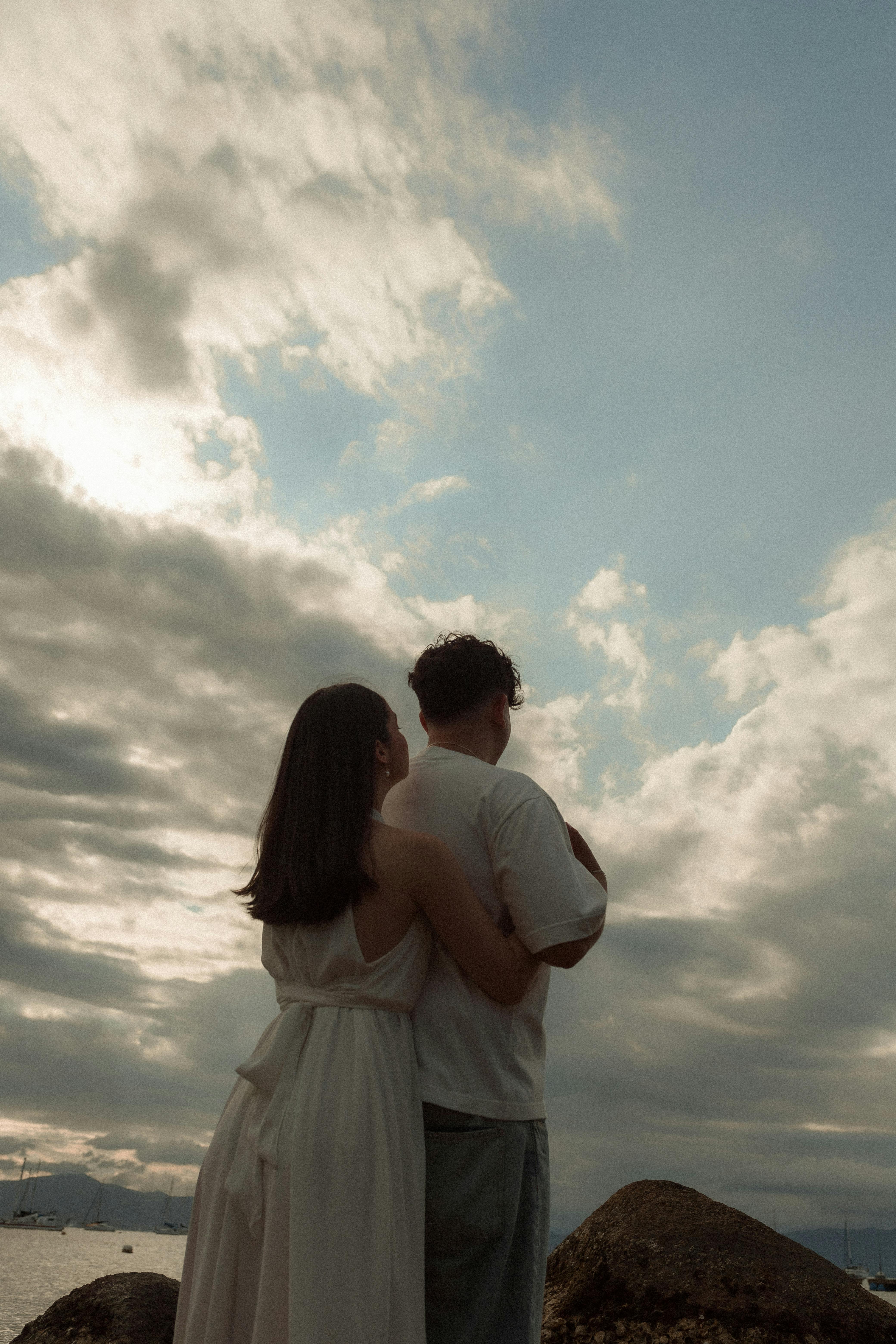 Couple Embracing Under Cloudy Sky · Free Stock Photo