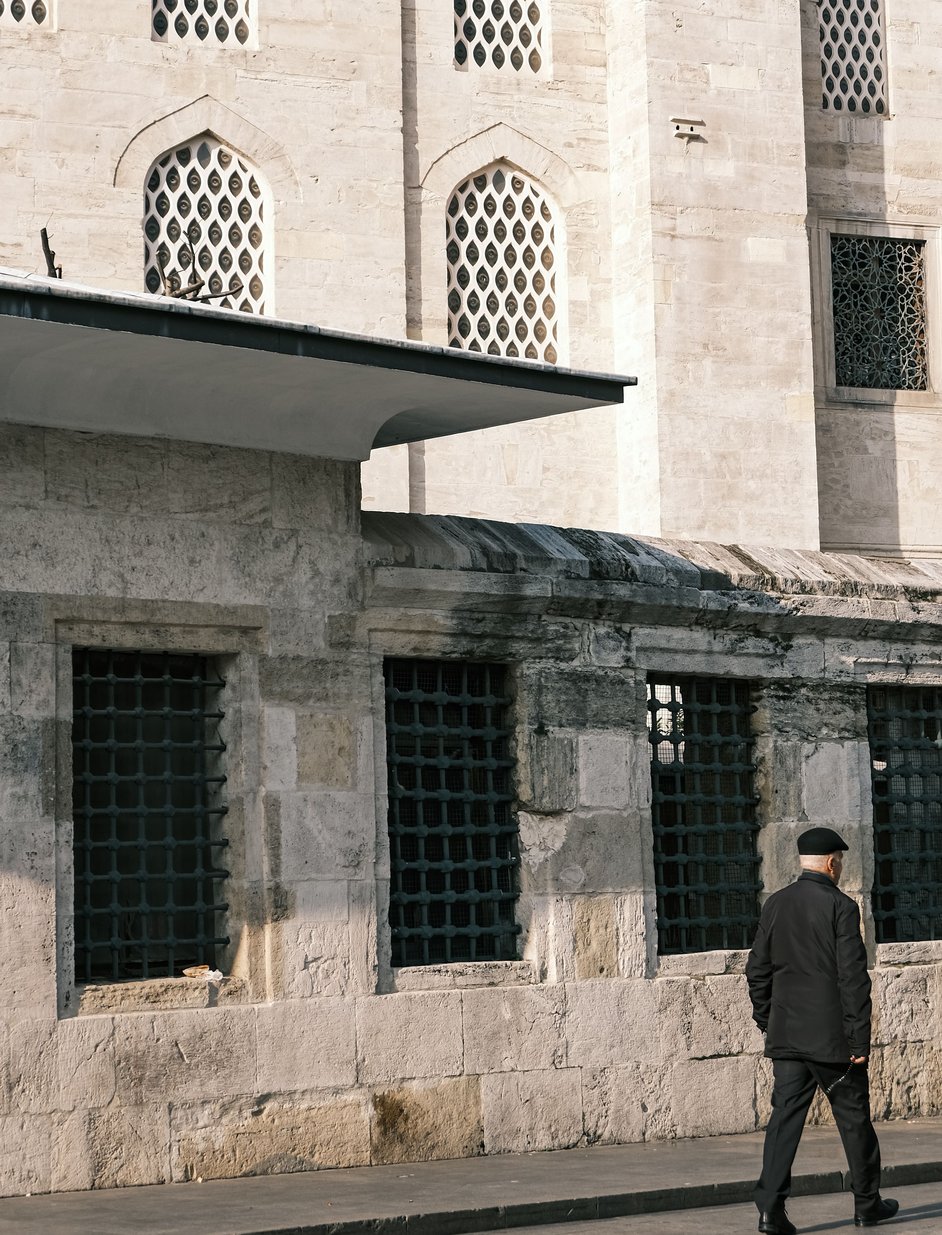 Man Walking by Historic Stone Building · Free Stock Photo