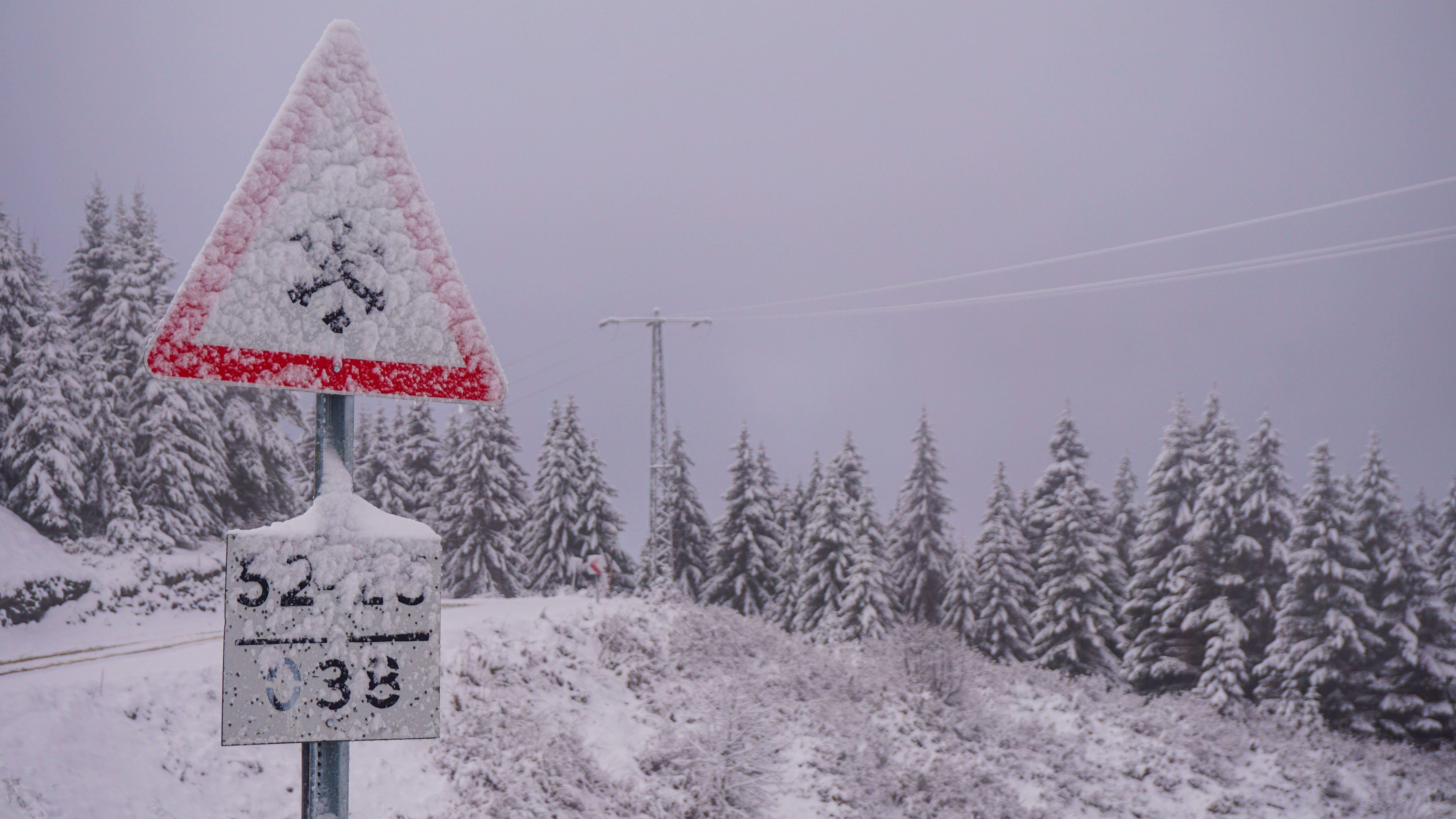 Snow-Covered Warning Sign on Wintery Road · Free Stock Photo