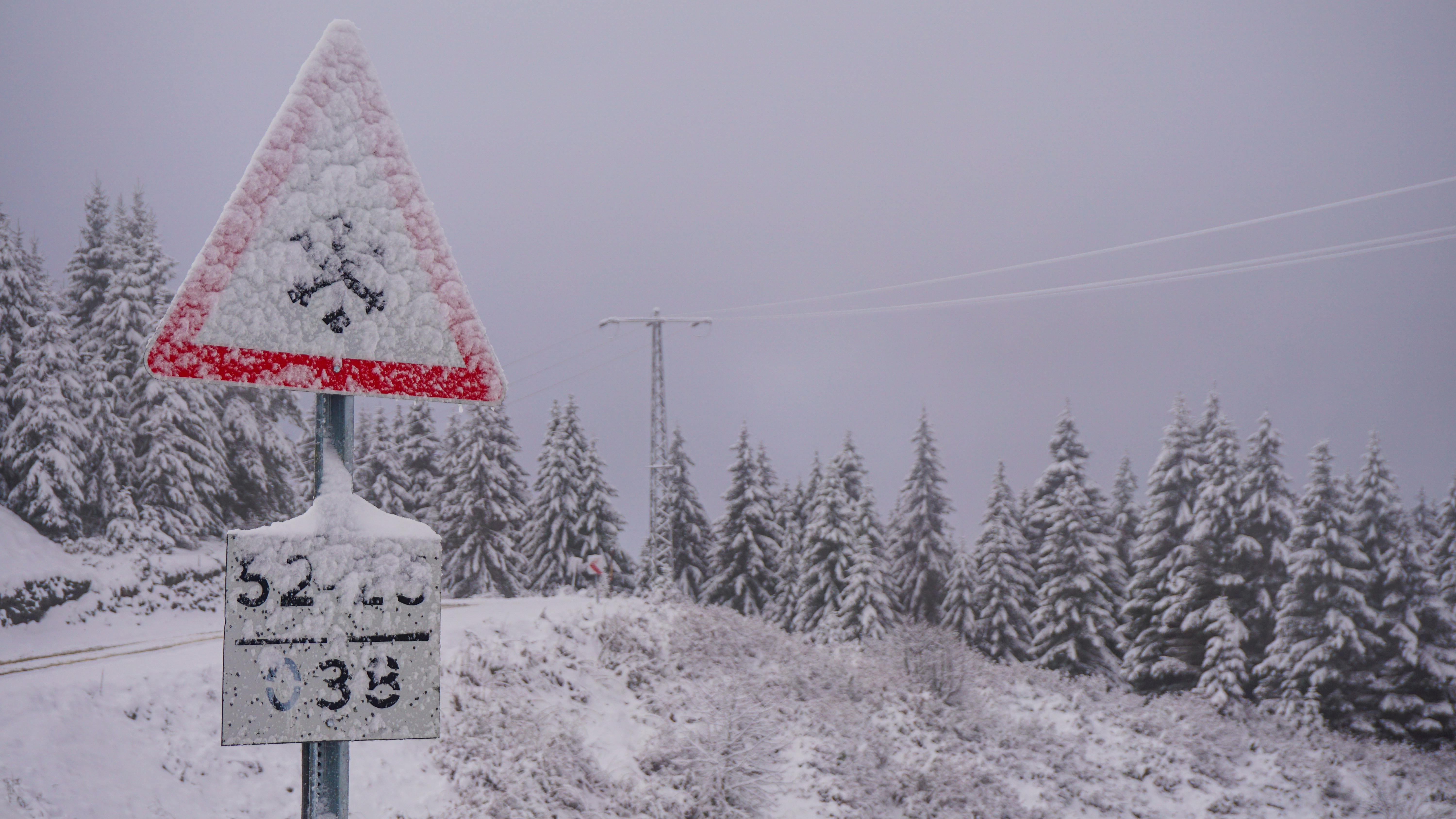 Snow-Covered Warning Sign on Wintery Road · Free Stock Photo