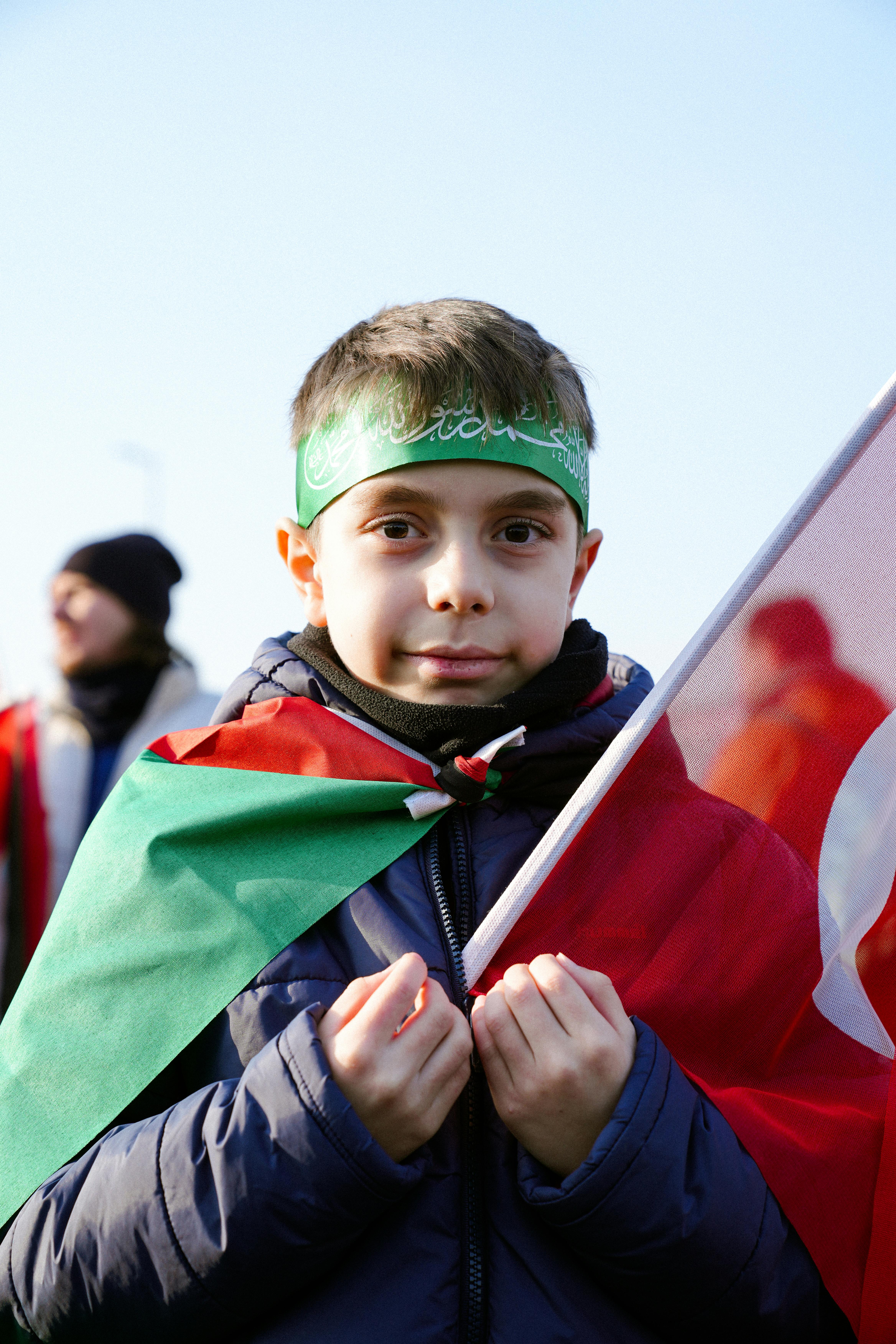 Young Boy Holding Flags at Outdoor Event · Free Stock Photo