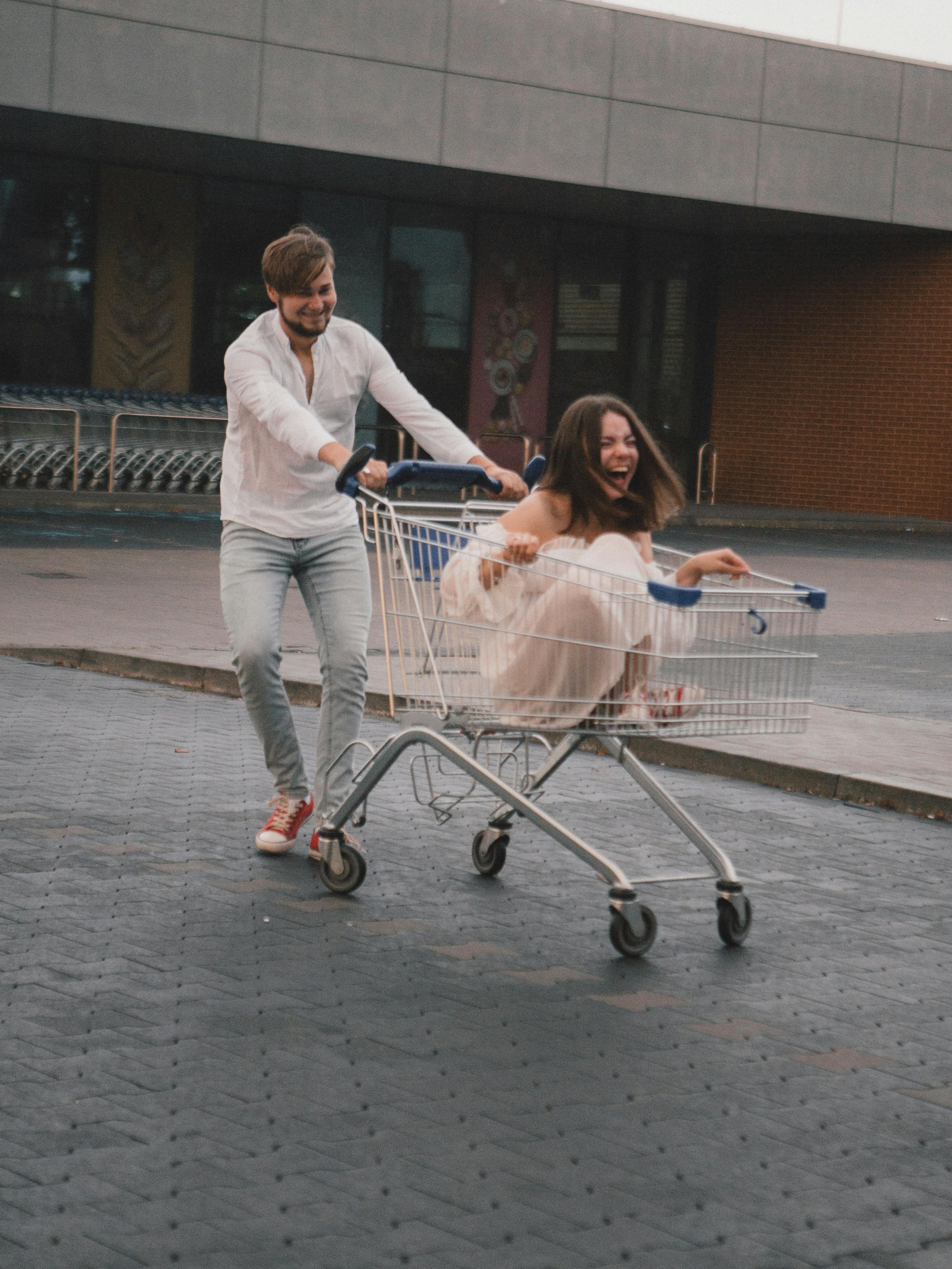 Playful Couple Enjoying Shopping Cart Ride · Free Stock Photo