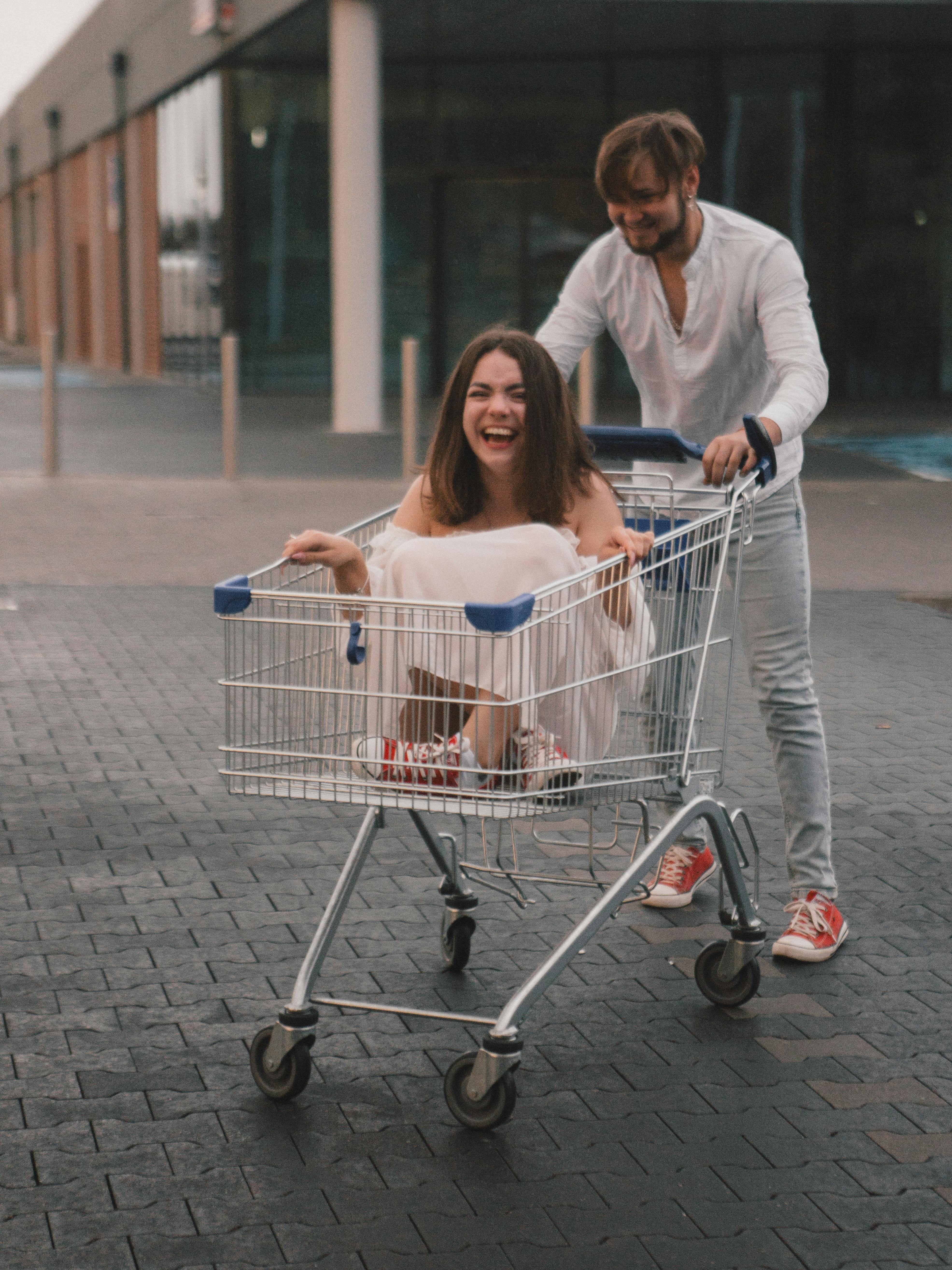 Young Couple Enjoys Playful Shopping Cart Ride · Free Stock Photo