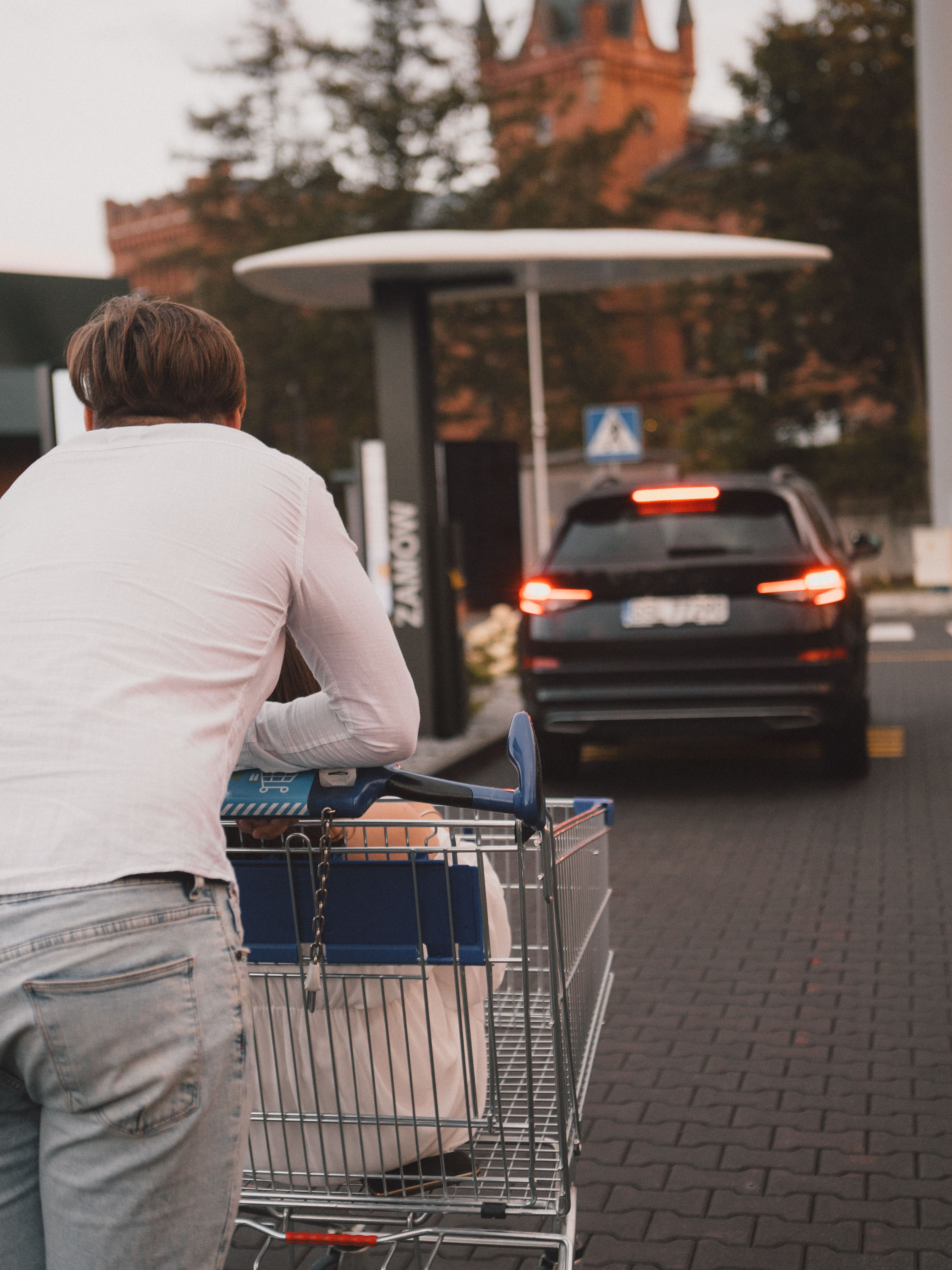 Man Pushing Shopping Cart in Parking Lot · Free Stock Photo