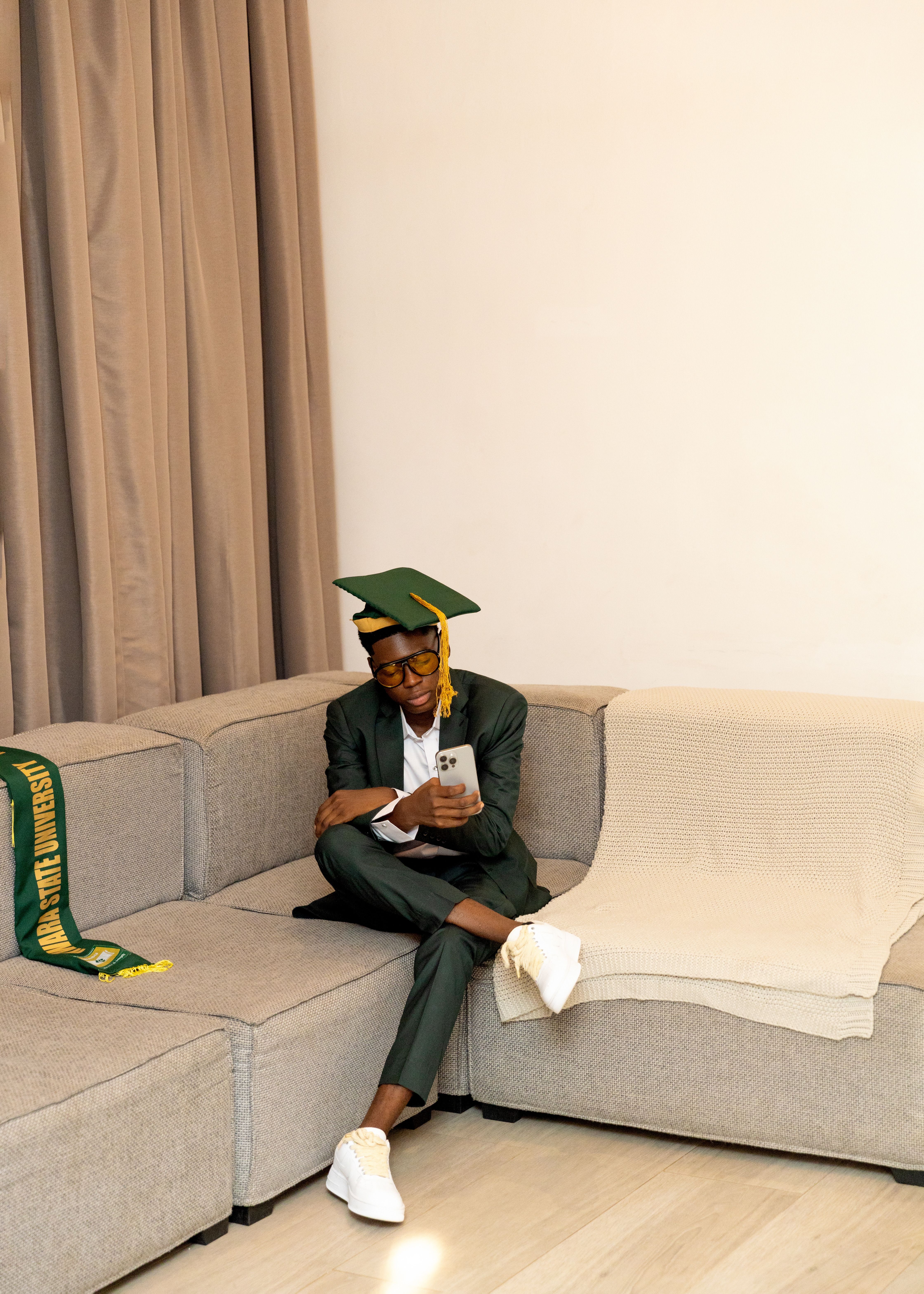 Young Graduate Relaxing at Home in Cap and Gown · Free Stock Photo