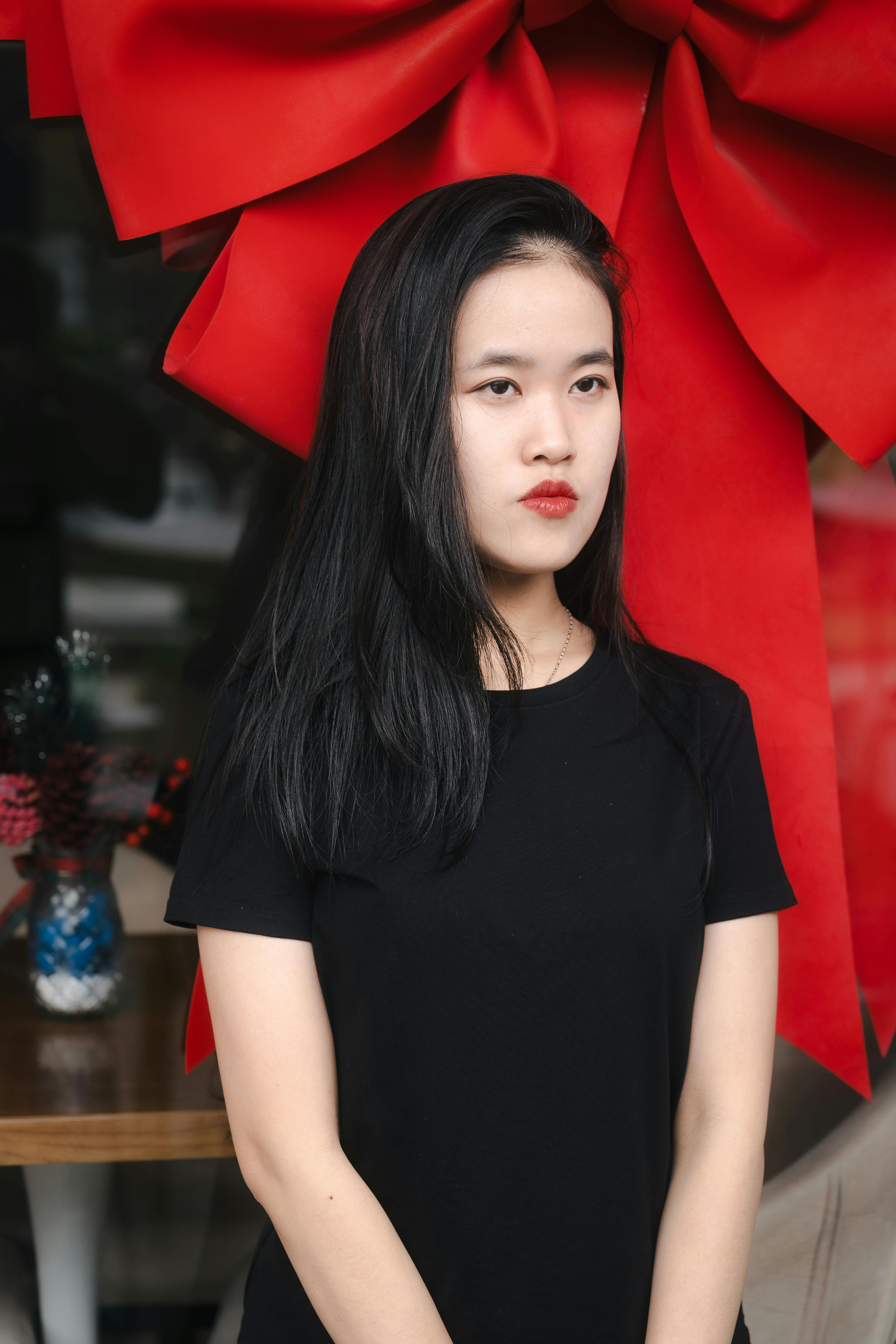 Mujer Joven Posando Con Un Gran Lazo Rojo Como Fondo · Foto de stock gratuita