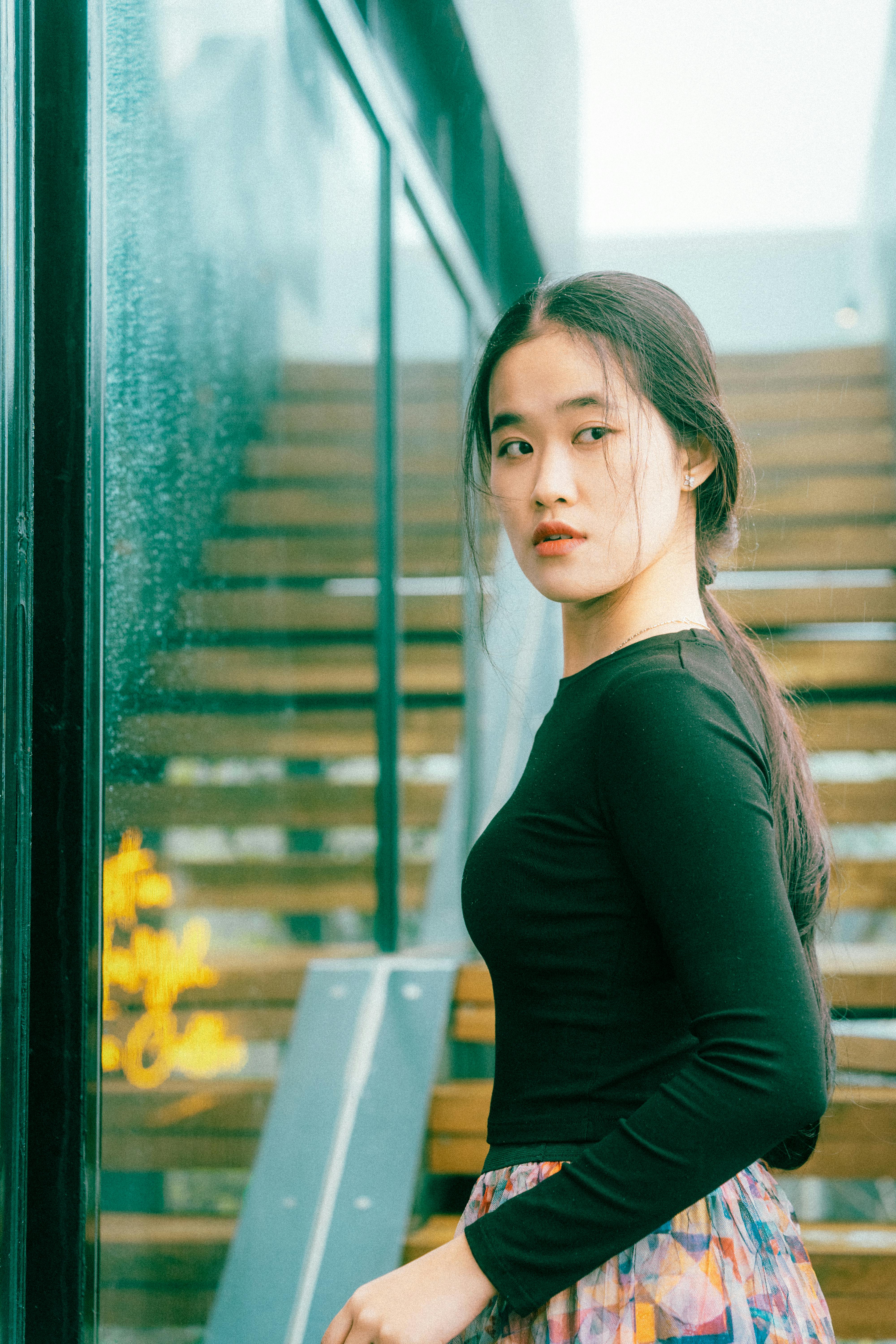 Young Woman Standing by Modern Staircase · Free Stock Photo