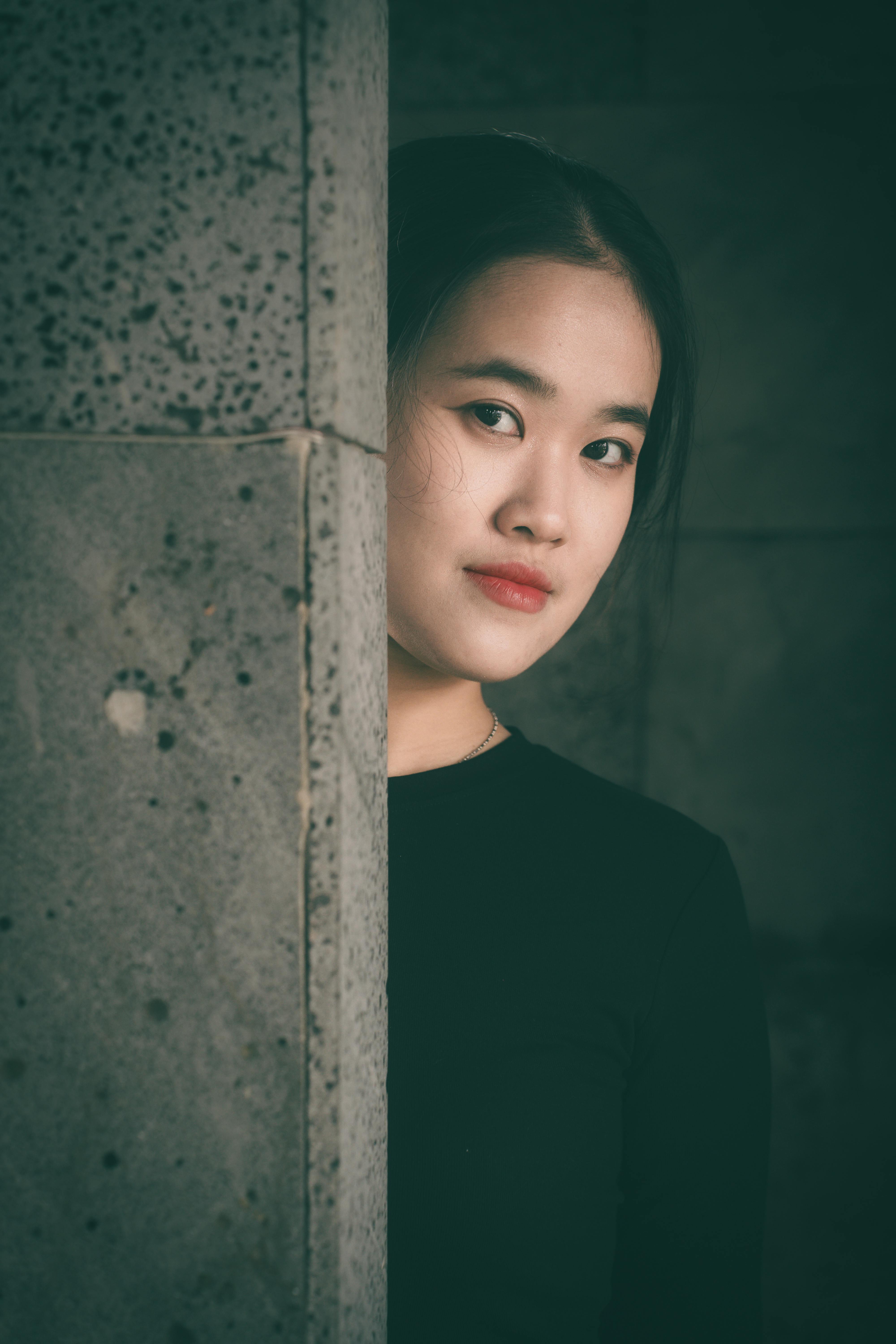 Portrait of a Woman Partially Hidden Behind Wall · Free Stock Photo