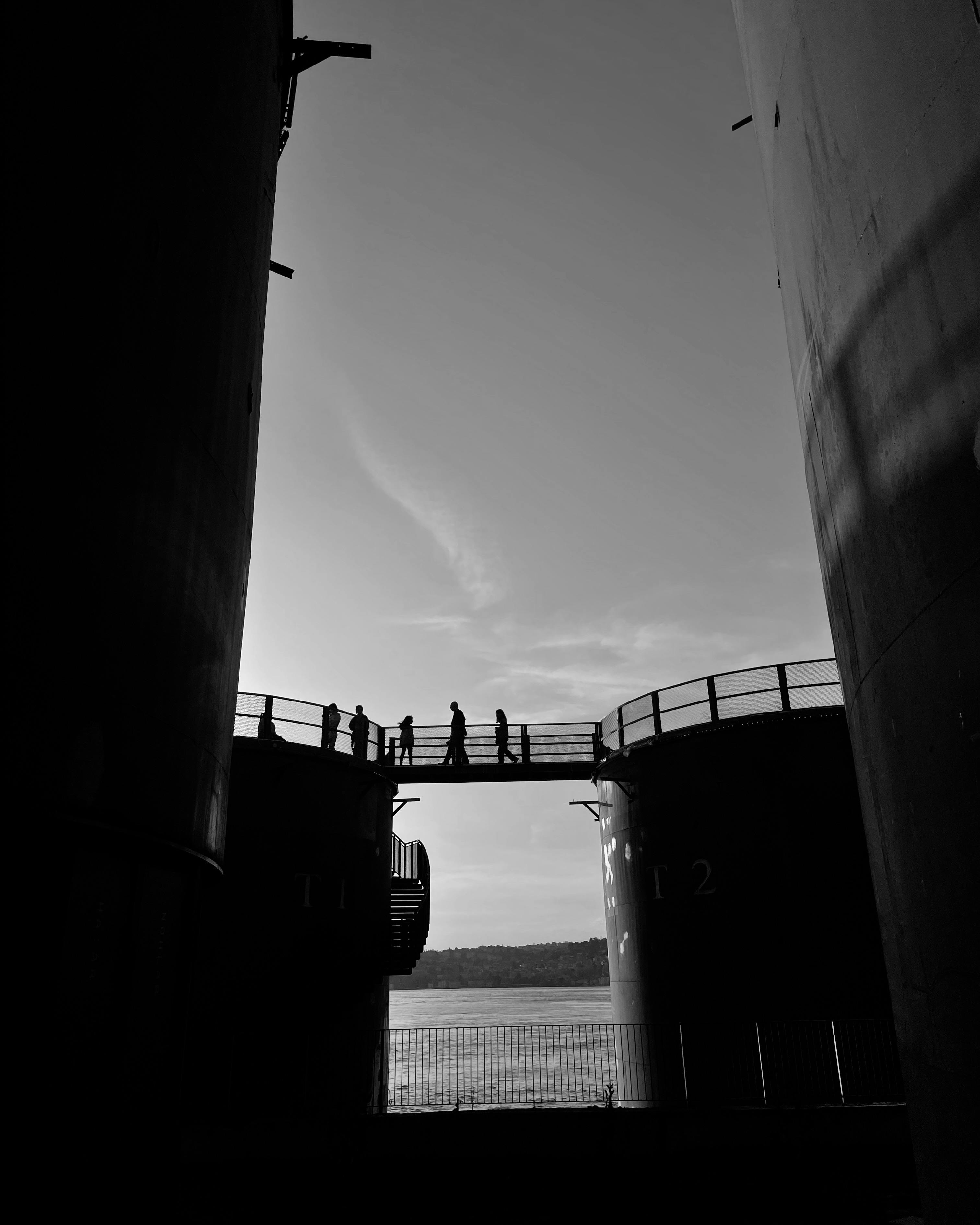 Silhouetted Figures on Industrial Walkway at Dusk · Free Stock Photo