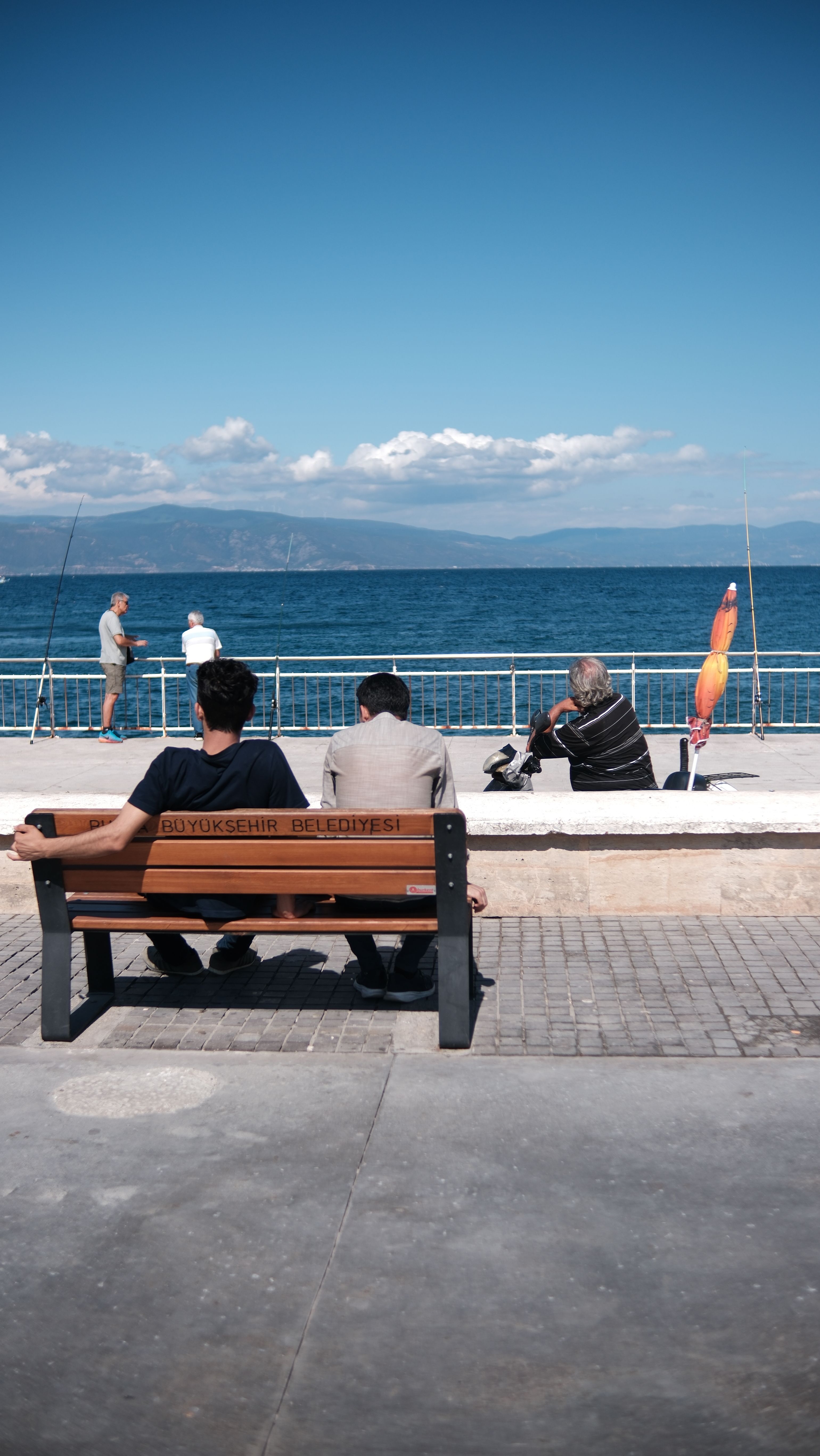 Relaxing Seaside View with People on Bench · Free Stock Photo