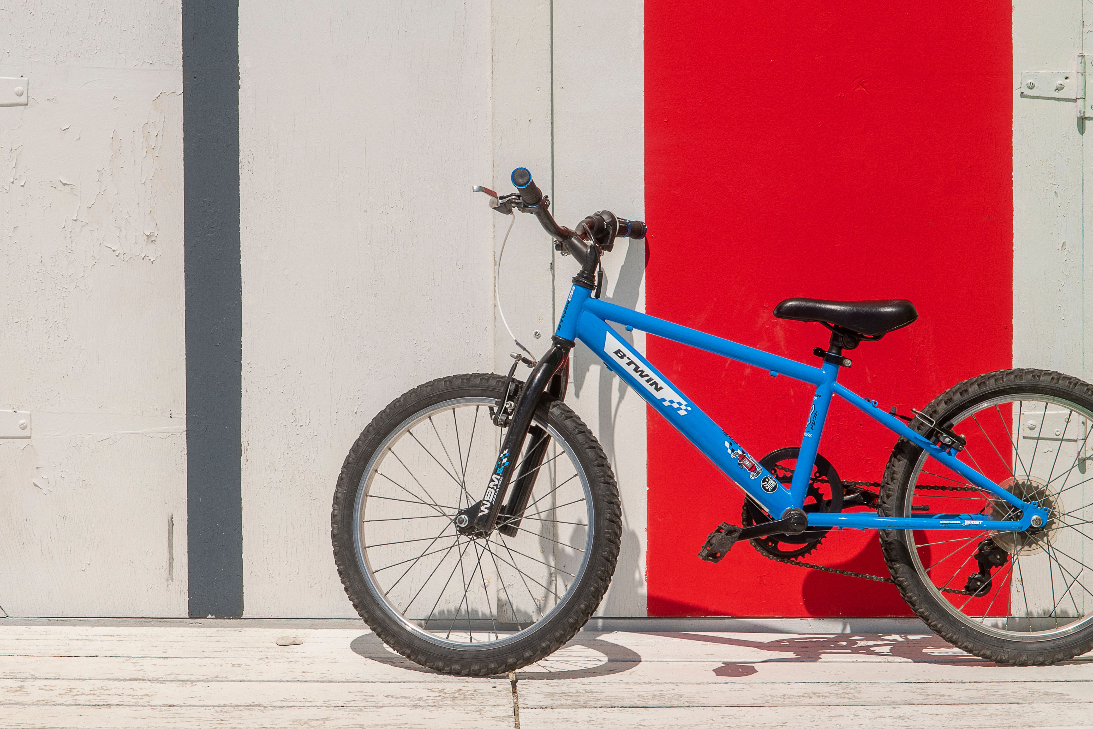 Vibrant Blue Bike Against Red and Grey Wall · Free Stock Photo