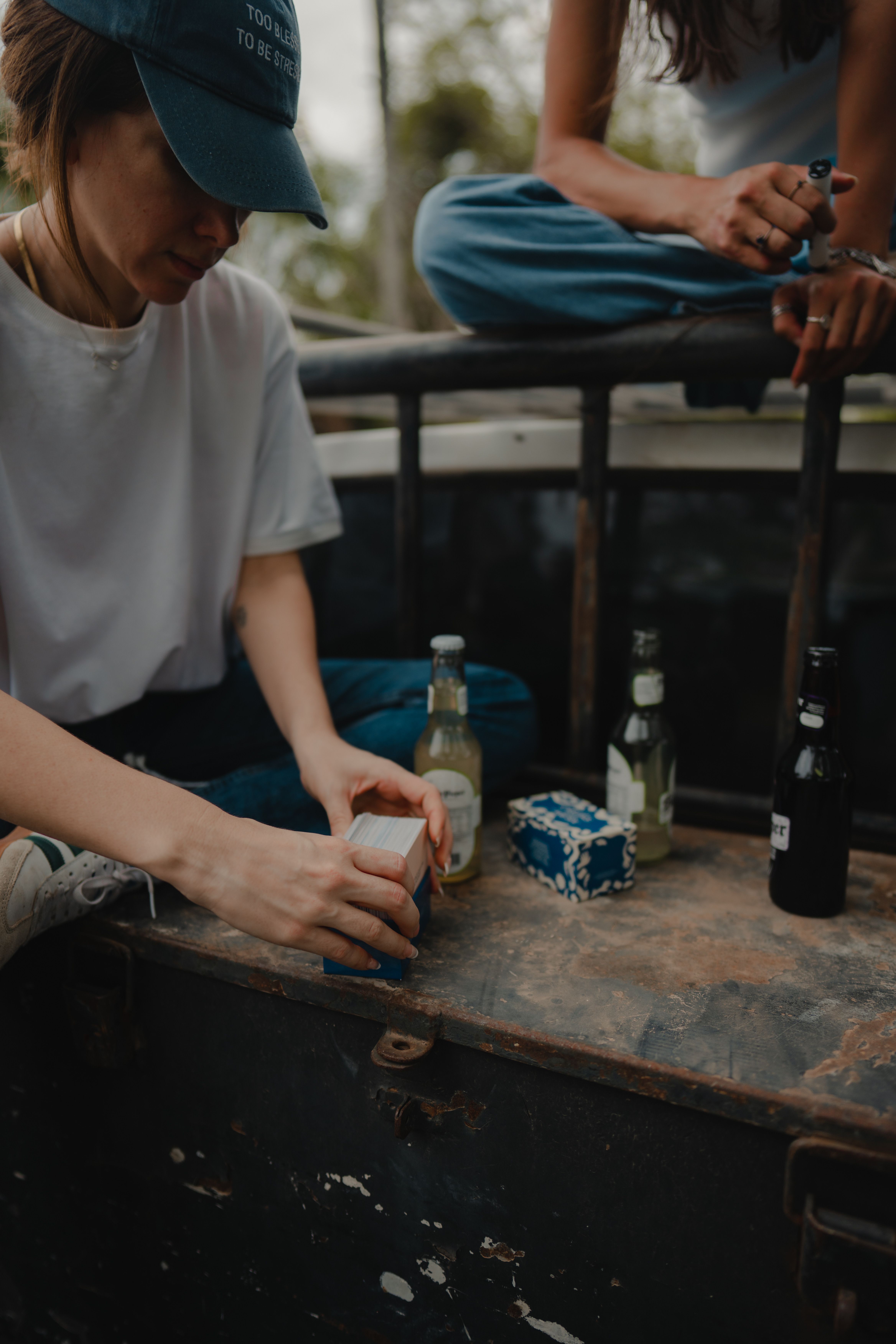 Youth Gathering Outdoors with Drinks and Cards · Free Stock Photo