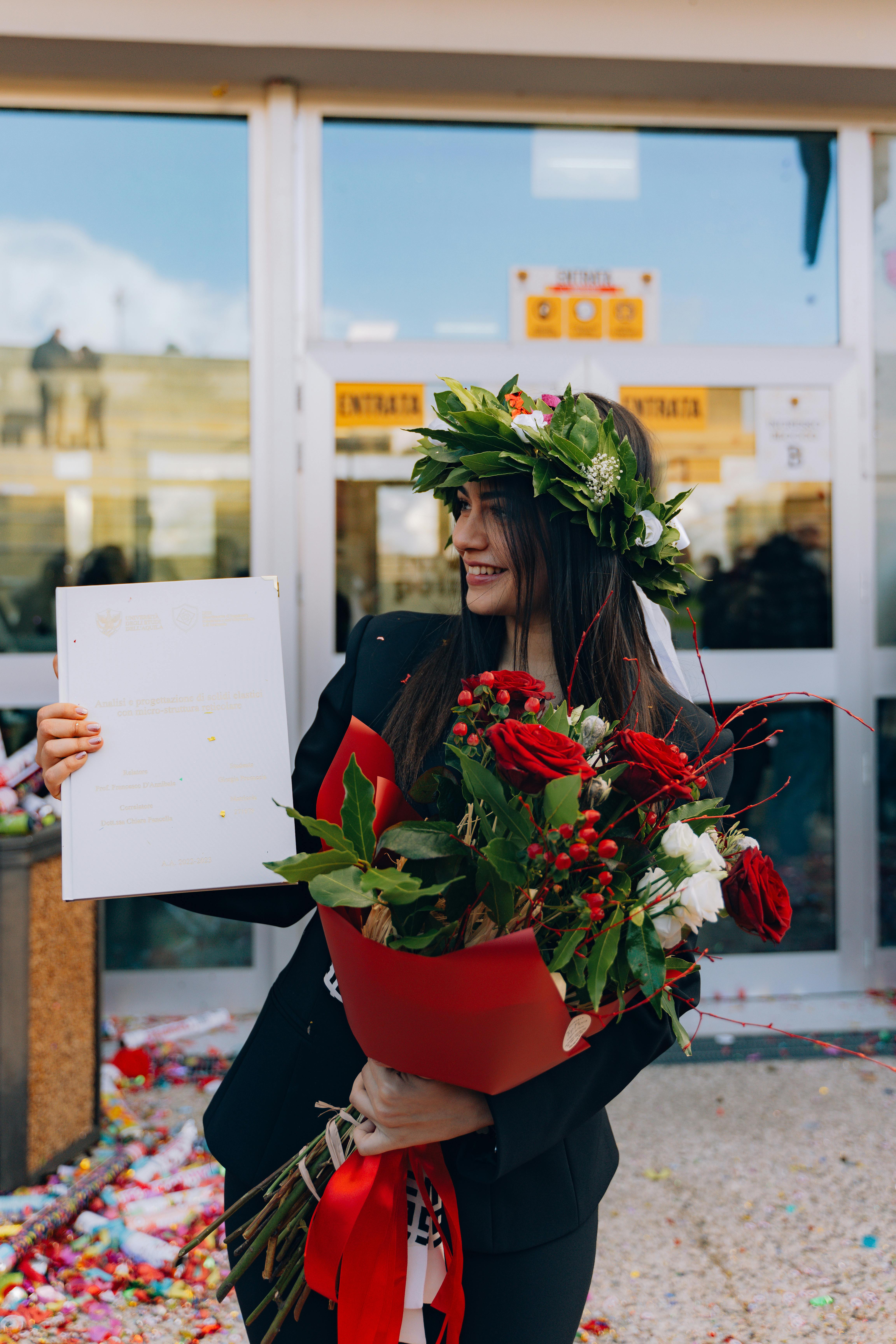 Joyful Graduate Holding Diploma and Flowers Outdoors · Free Stock Photo