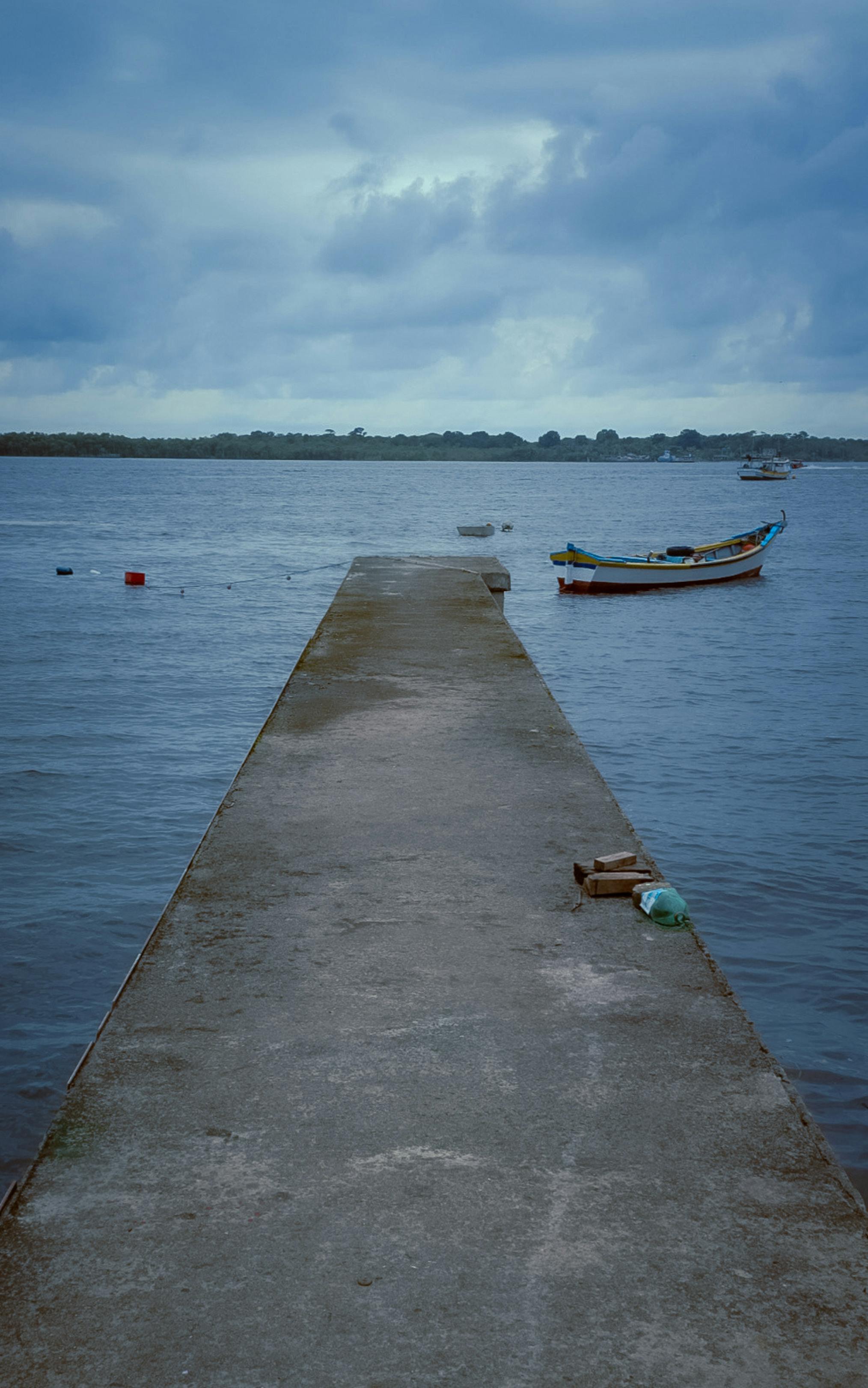 Serene Jetty View with Wooden Boat on Calm Sea · Free Stock Photo