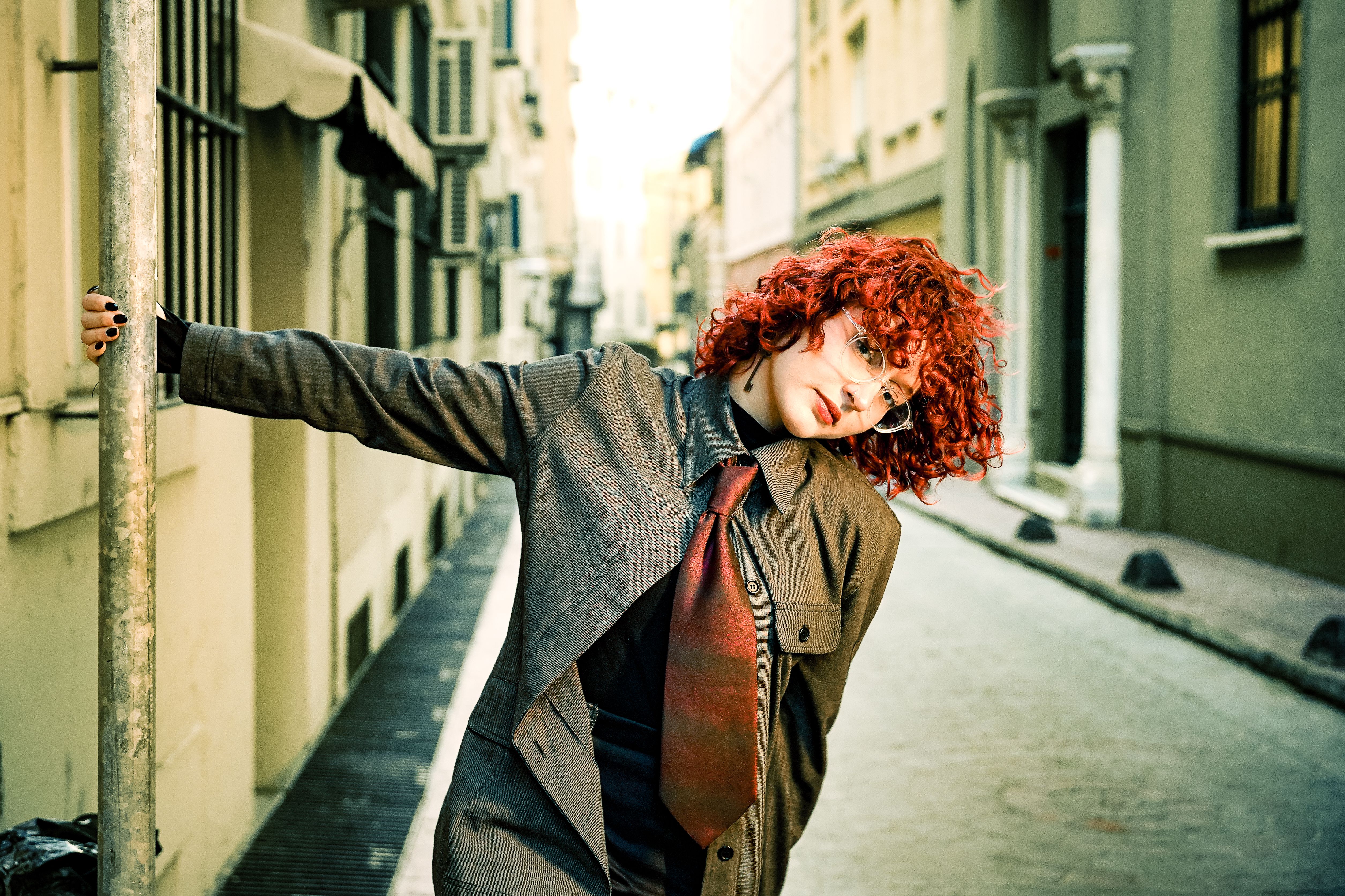 Stylish woman with red curly hair in urban alley · Free Stock Photo