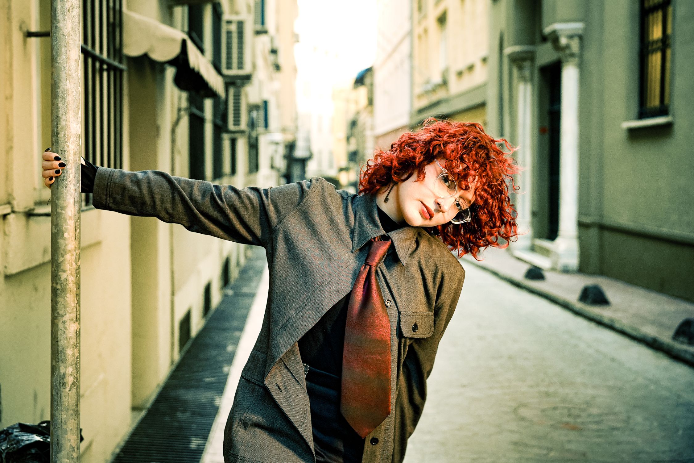 Stylish woman with red curly hair in urban alley · Free Stock Photo