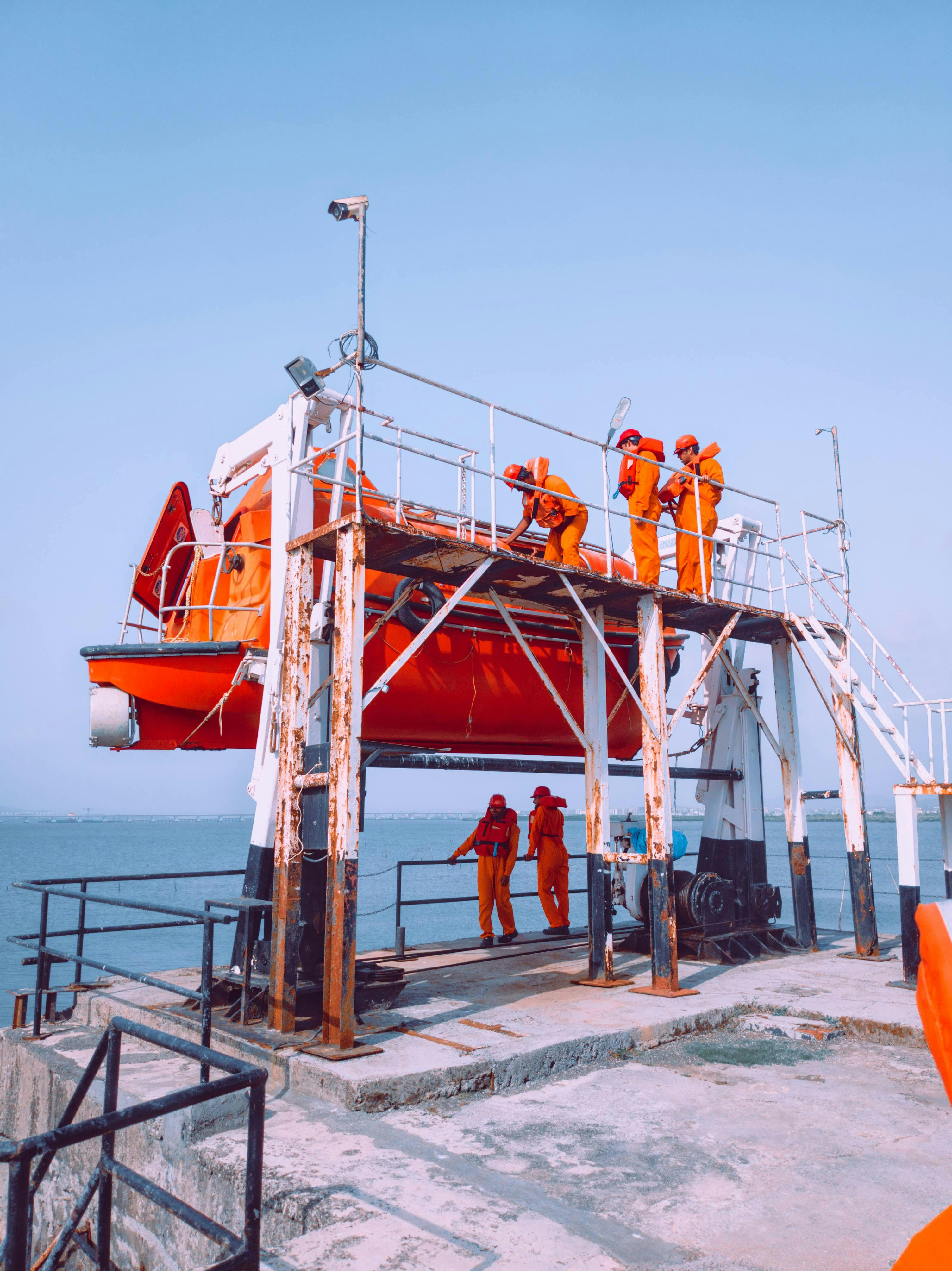 Workers in Orange Gear on Lifeboat Station by the Sea · Free Stock Photo