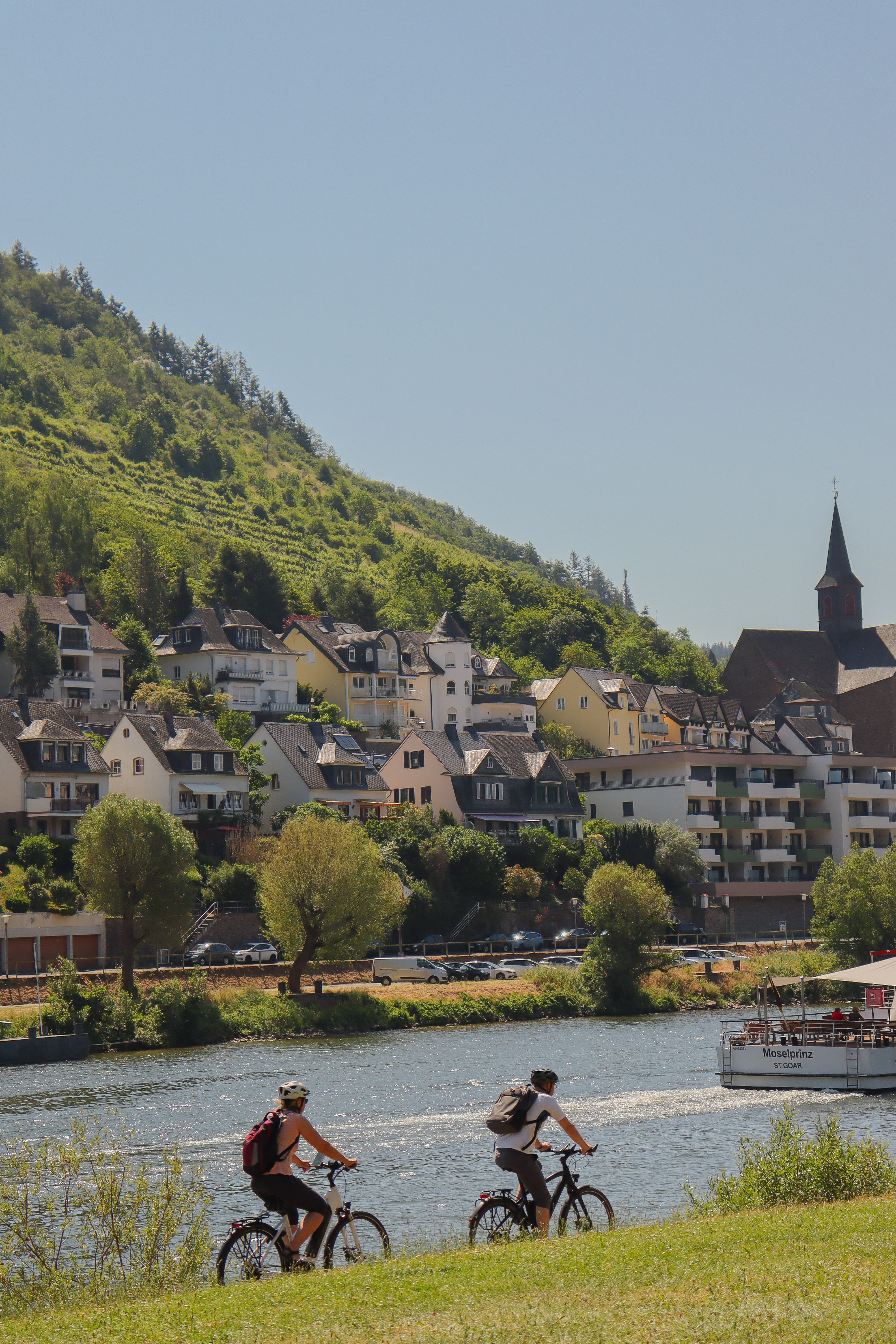 Cyclists Enjoying Scenic Riverfront in Summer · Free Stock Photo