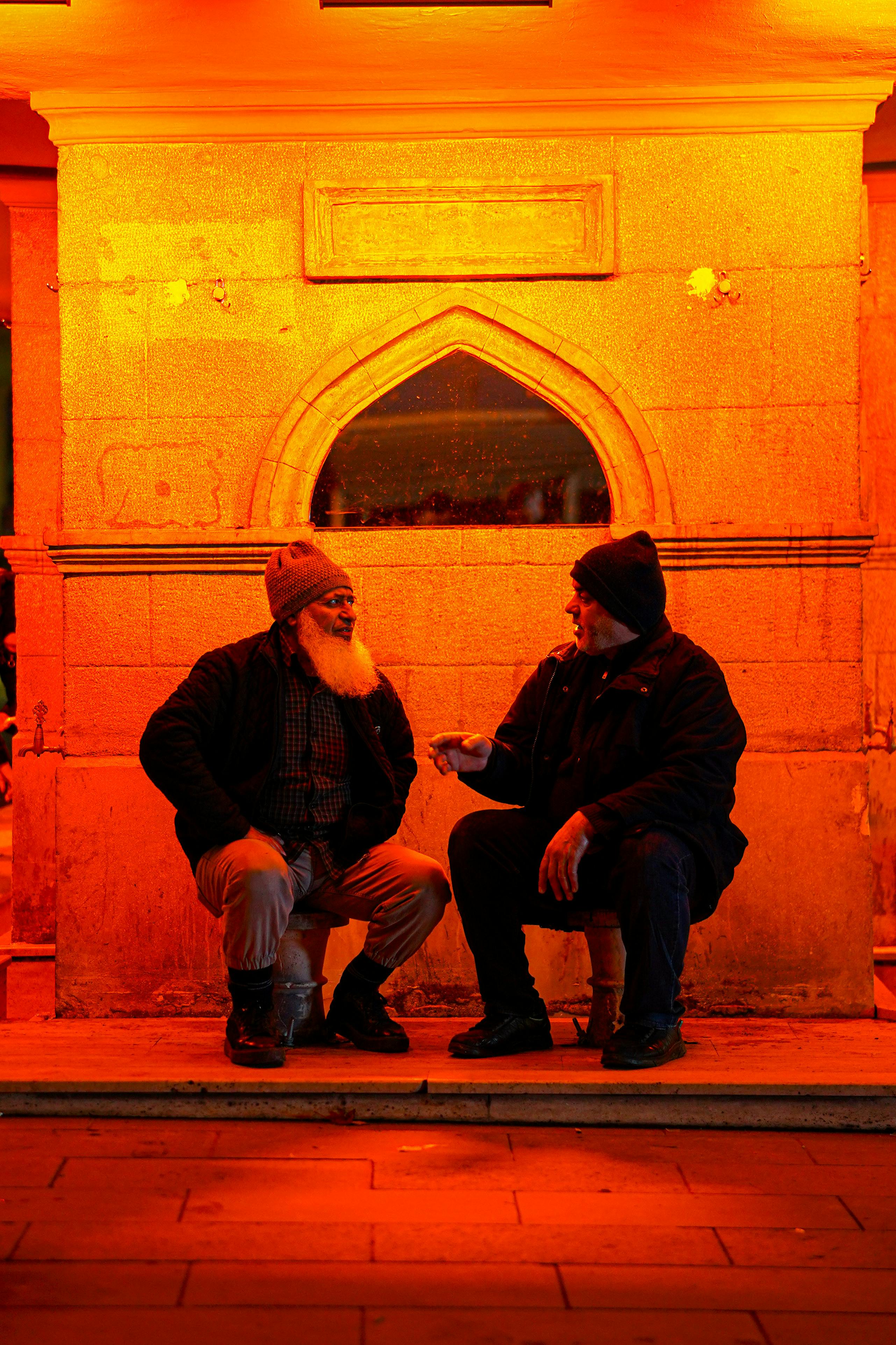 Two Men Conversing on Orange Lit Street · Free Stock Photo