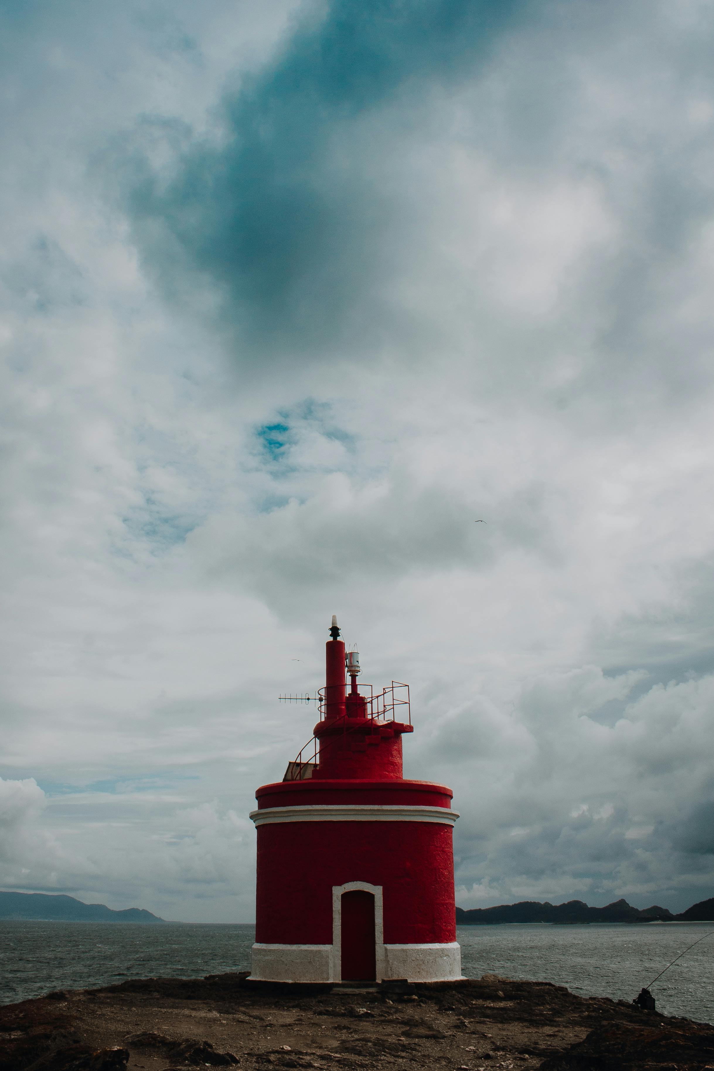 Red Lighthouse on Top of Hills Beside Sea · Free Stock Photo