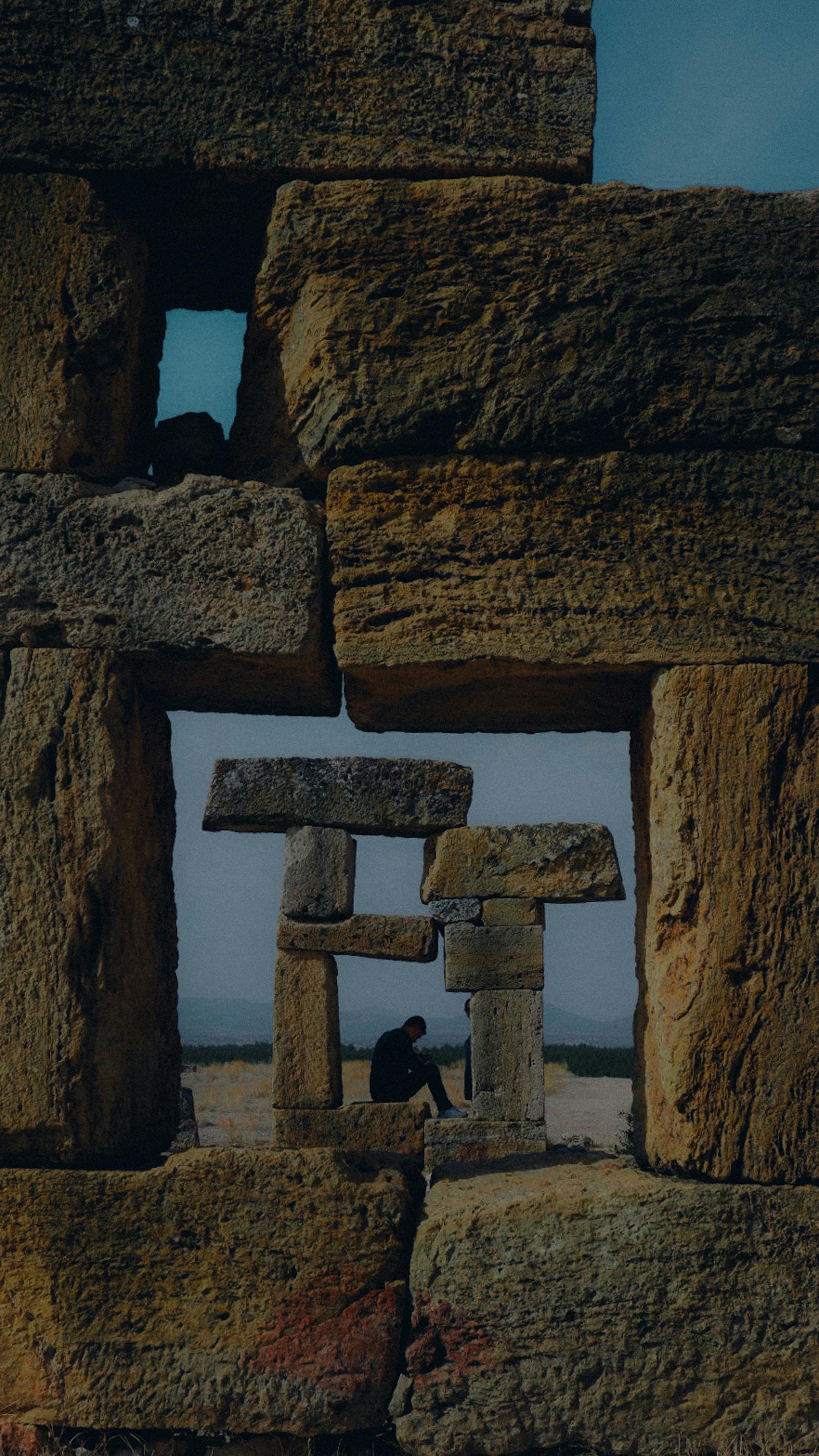 Stone Structure with Contemplative Figure Outdoors · Free Stock Photo