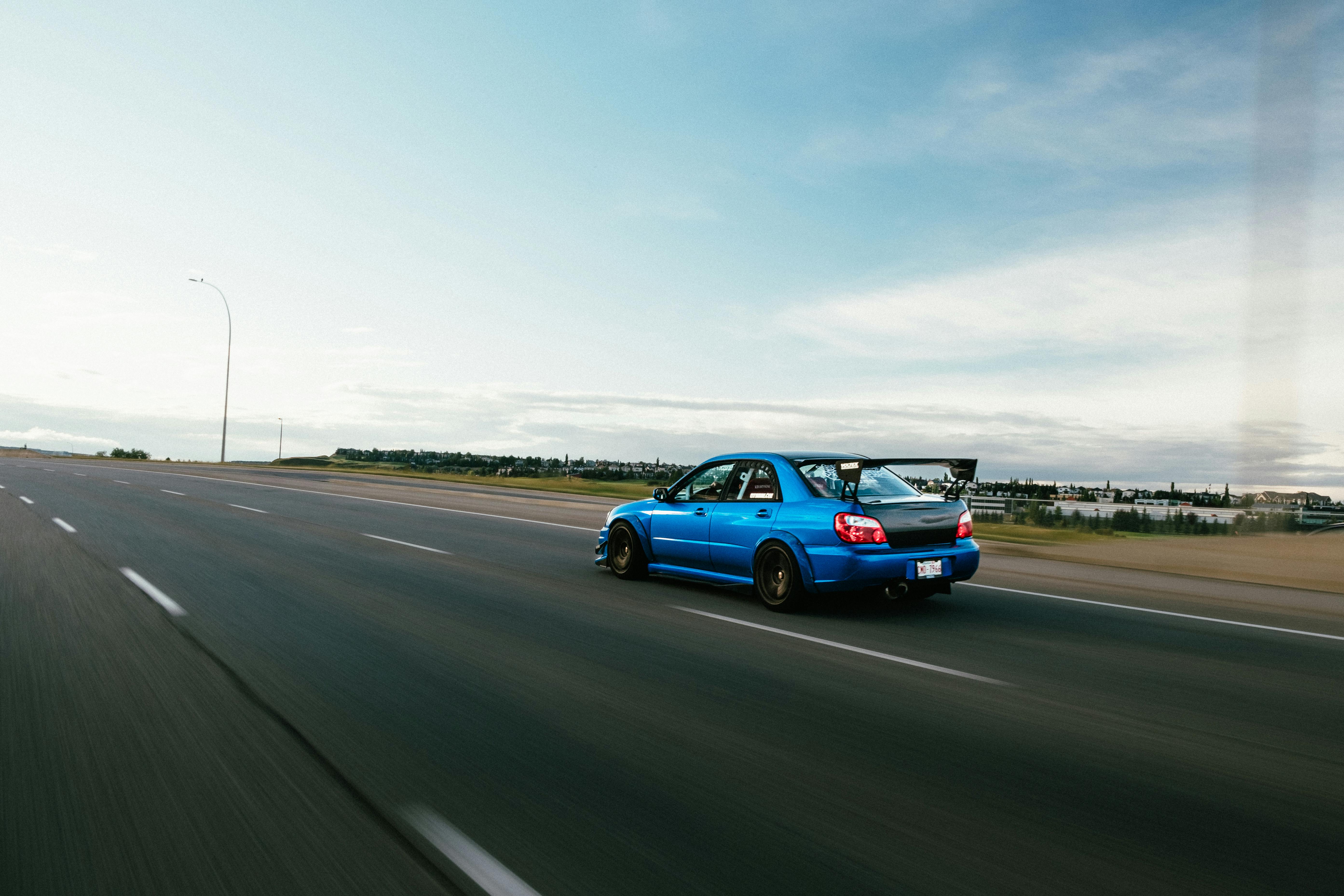 High-Speed Blue Subaru WRX STI on Highway · Free Stock Photo
