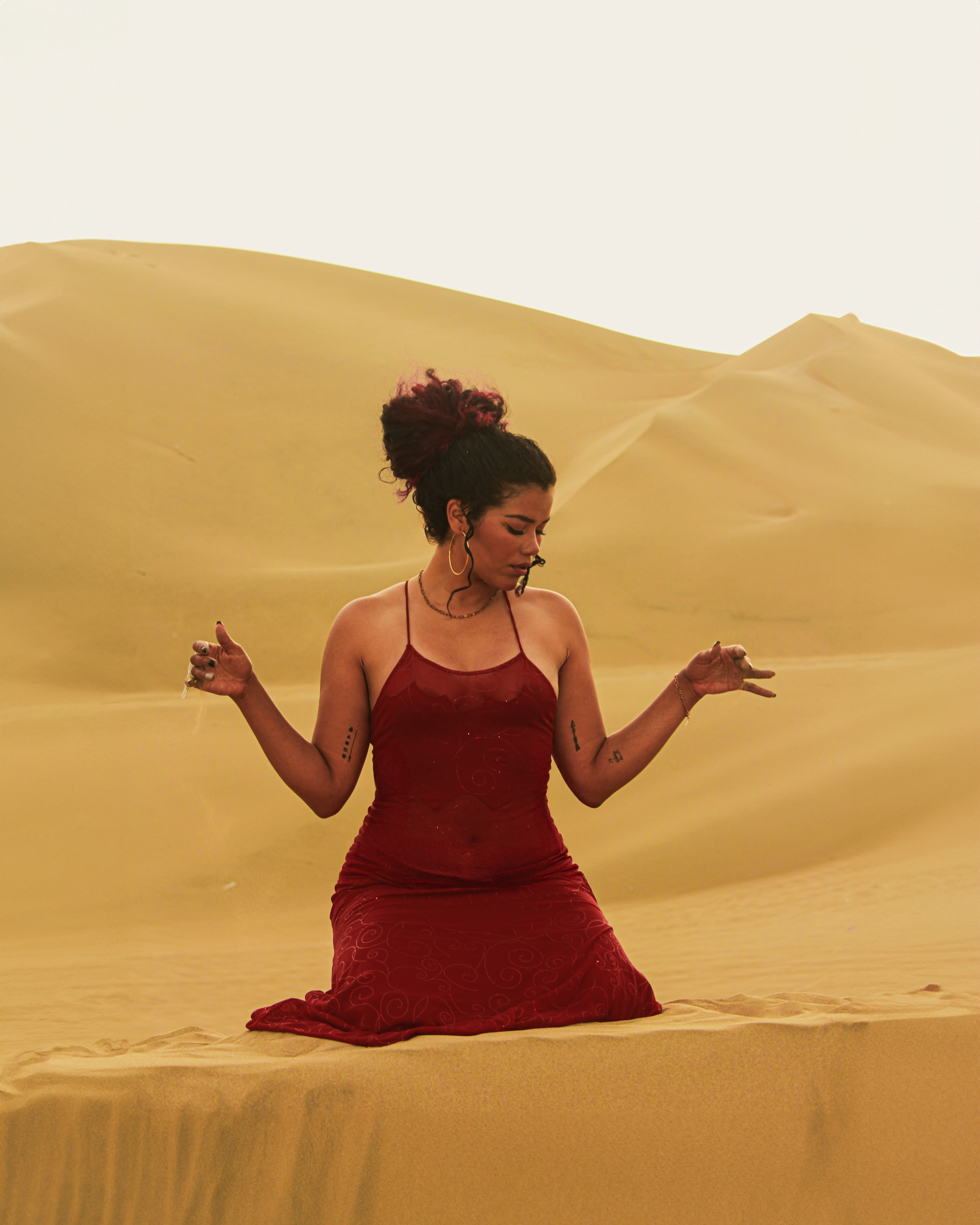 Woman in Red Dress Sitting in Desert Landscape · Free Stock Photo