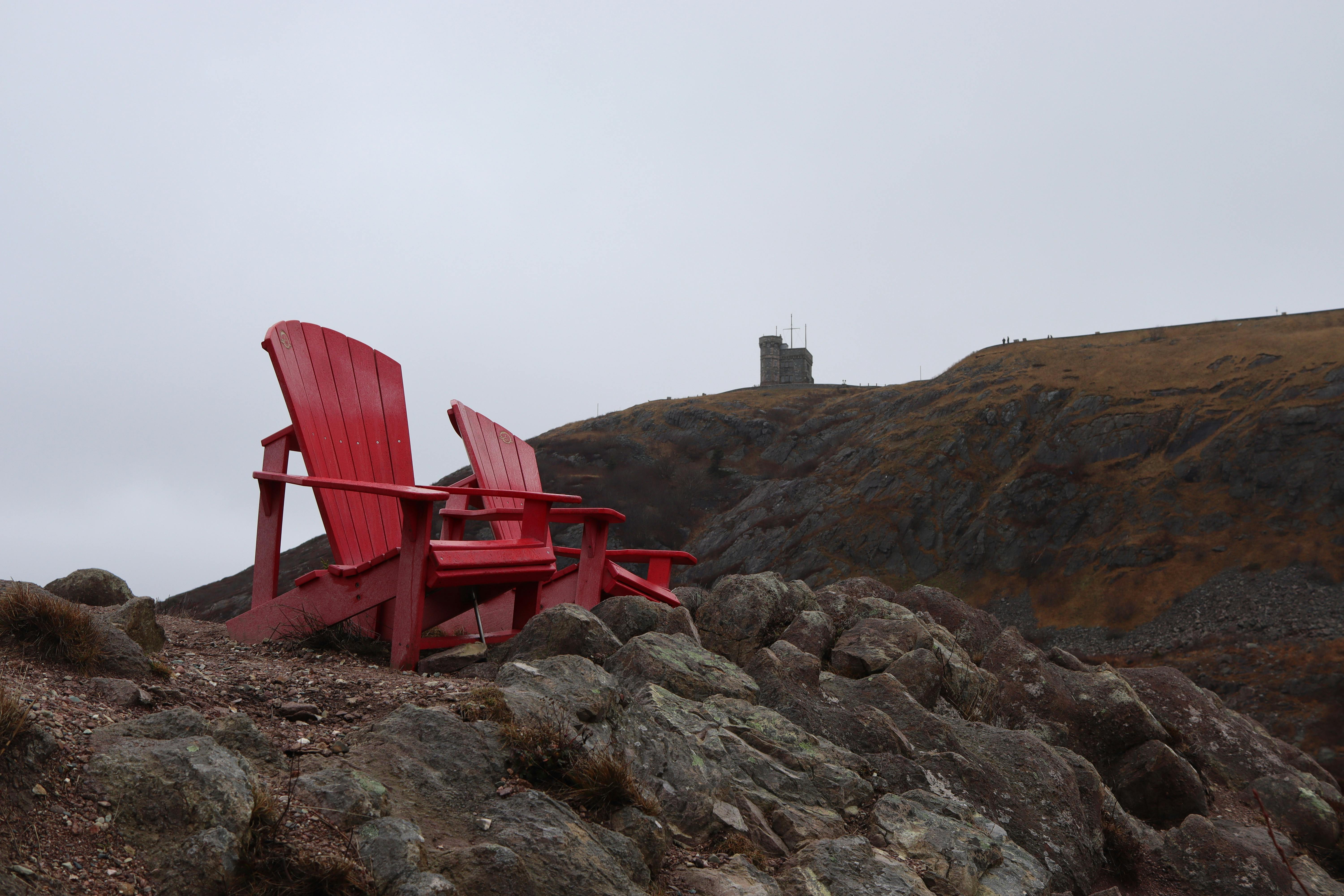 Red Adirondack Chairs Overlooking Rocky Hillside · Free Stock Photo