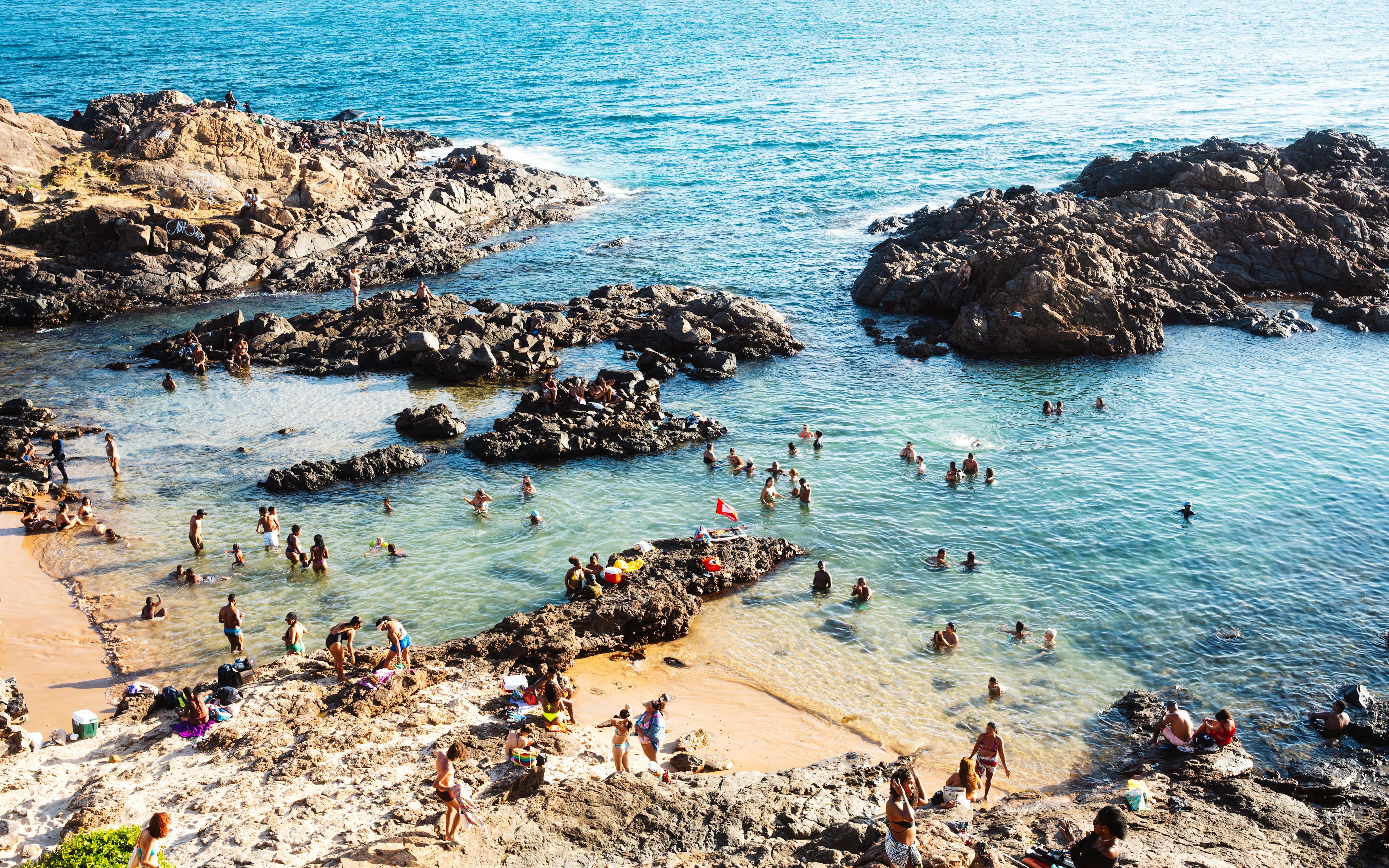 Cala De Playa Llena De Gente Con Costa Rocosa · Foto de stock gratuita