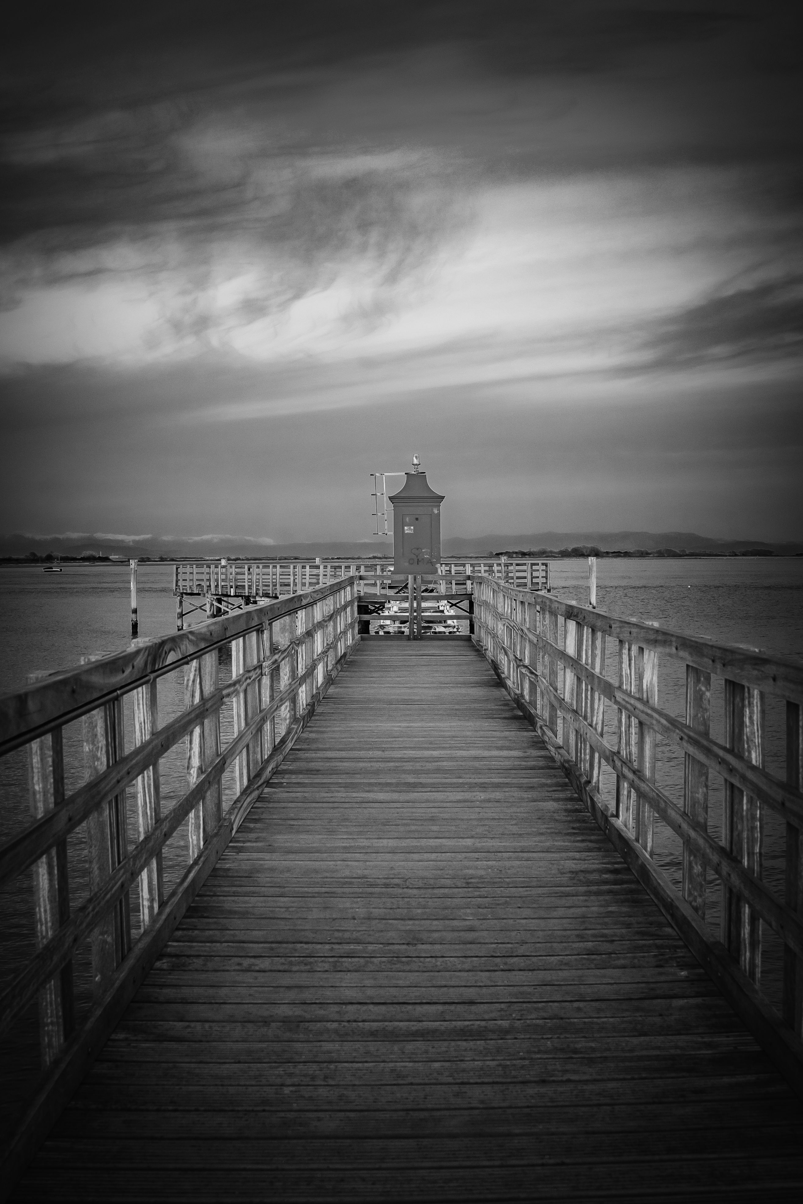 Gloomy Pier Leading to Lighthouse Under Grey Skies · Free Stock Photo