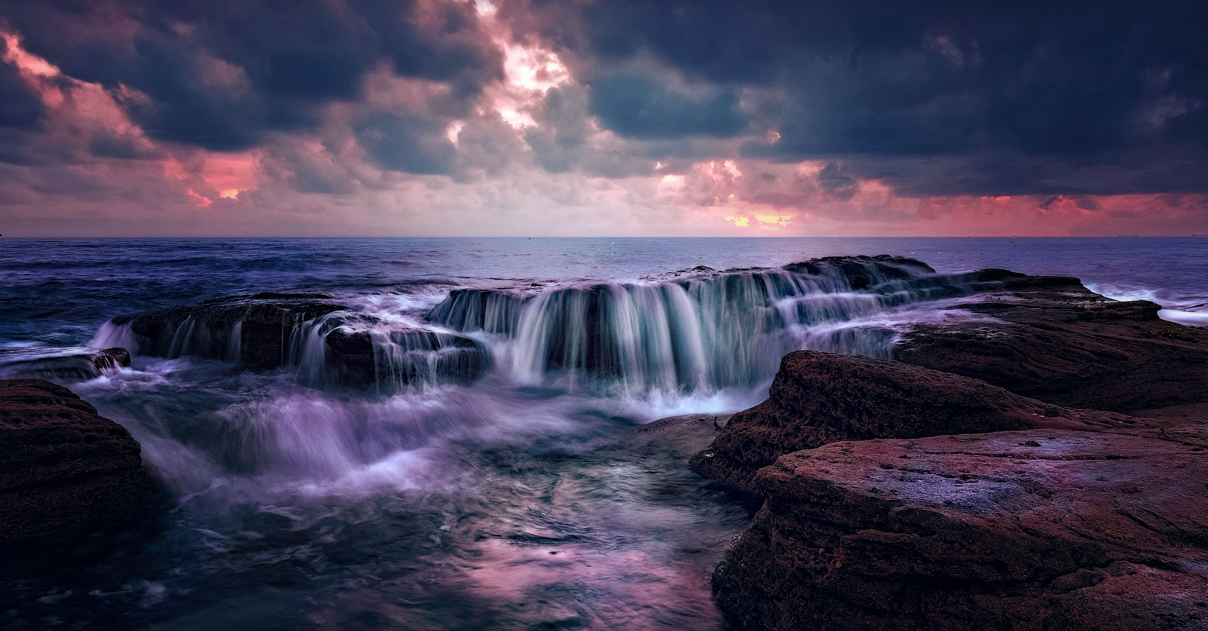 Dramatic seaside waterfall at sunset · Free Stock Photo