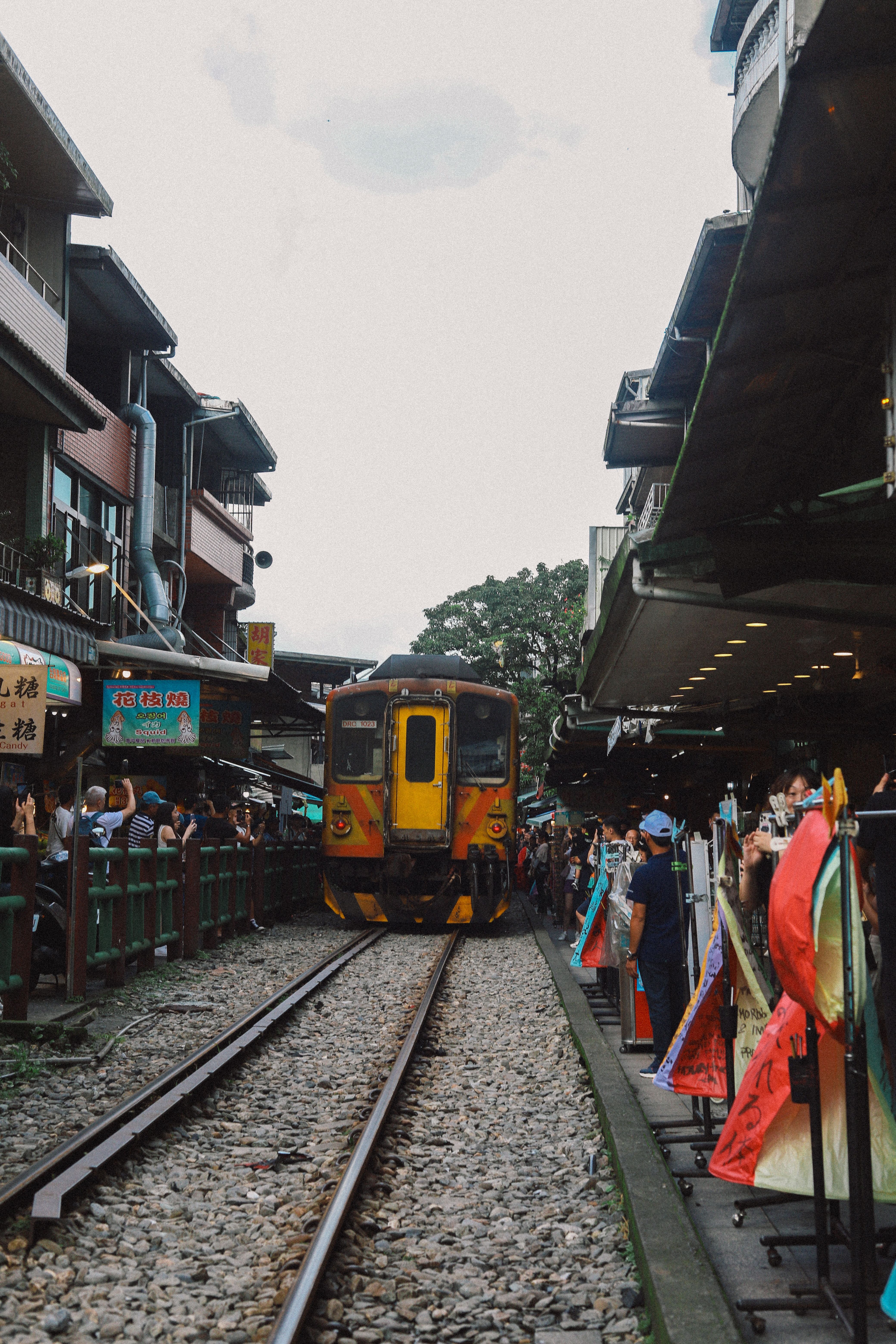 Colorful Train Passing Through Busy Street Market · Free Stock Photo