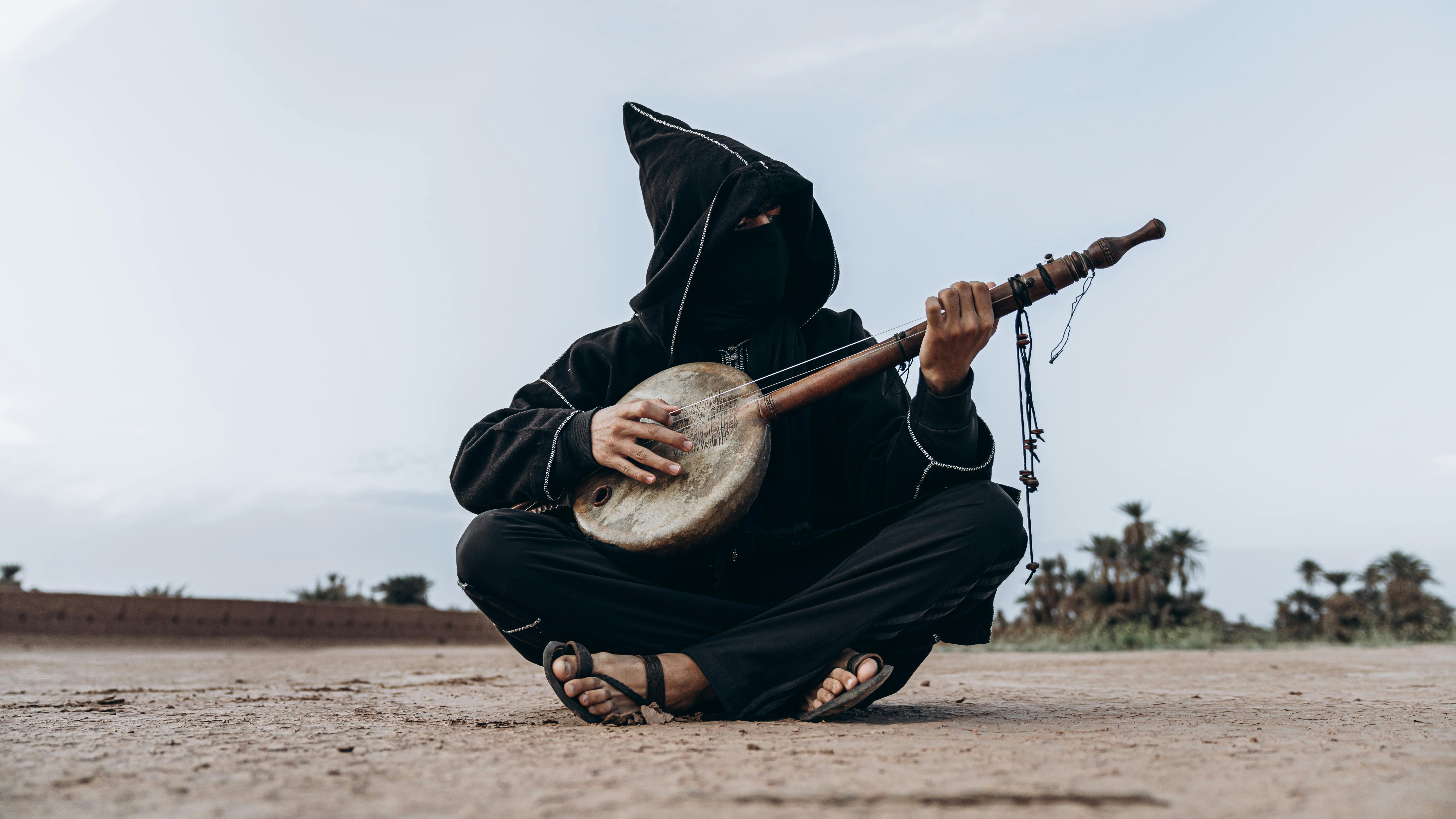 Traditional Moroccan Musician in Desert Landscape · Free Stock Photo