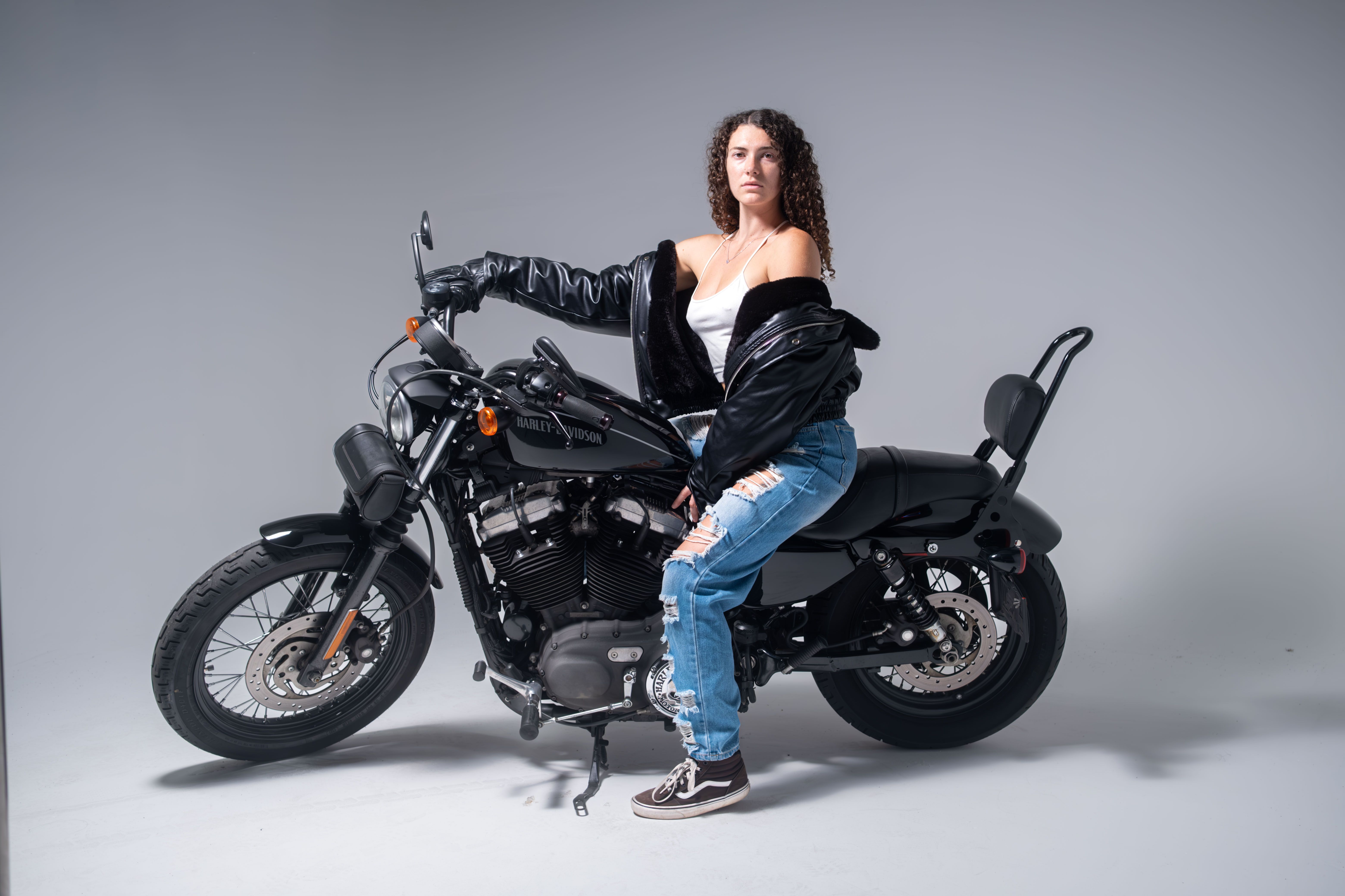 Stylish Woman Posing with Black Motorcycle in Studio · Free Stock Photo