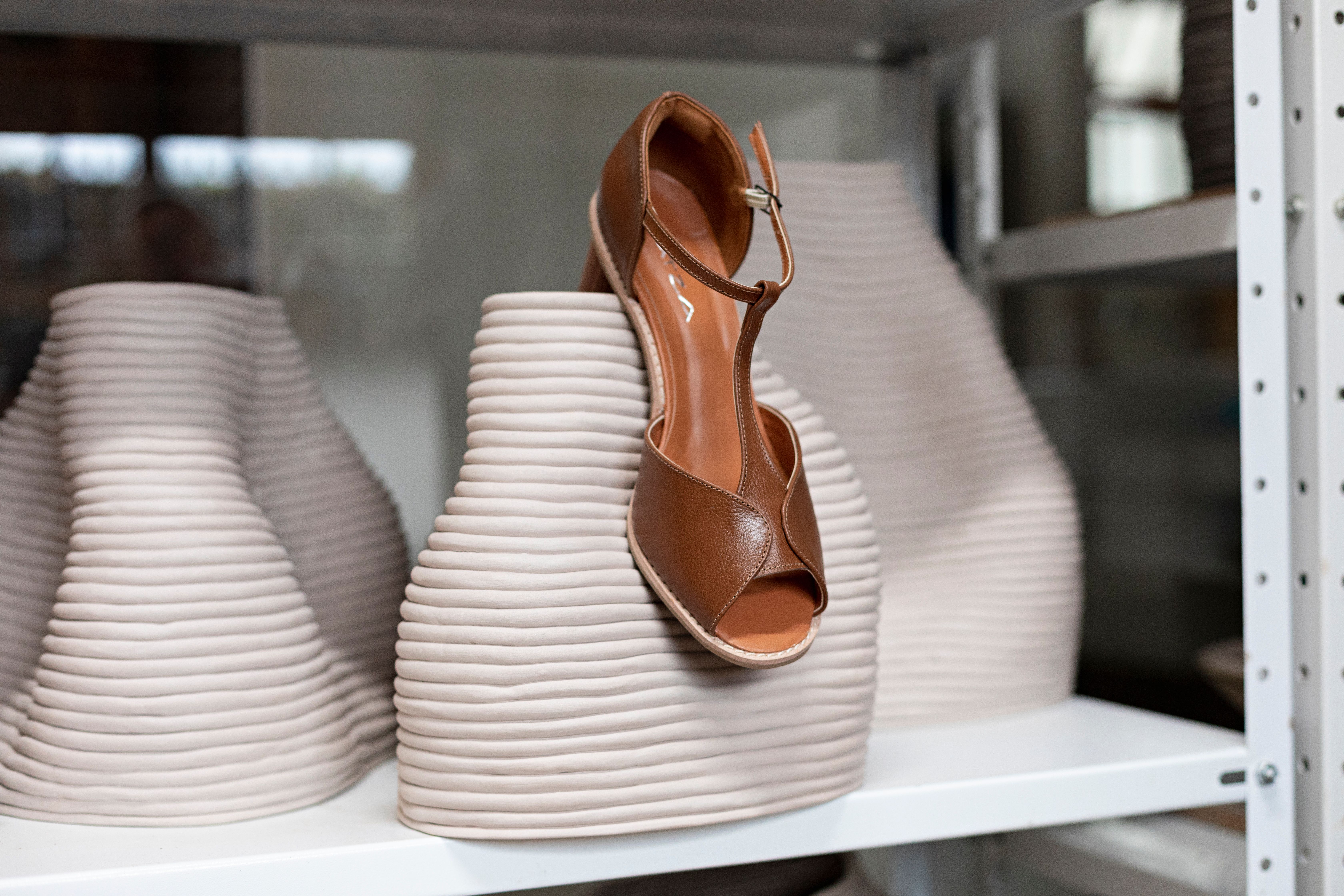 Elegant Brown Leather Shoe on Textured Vase Display · Free Stock Photo