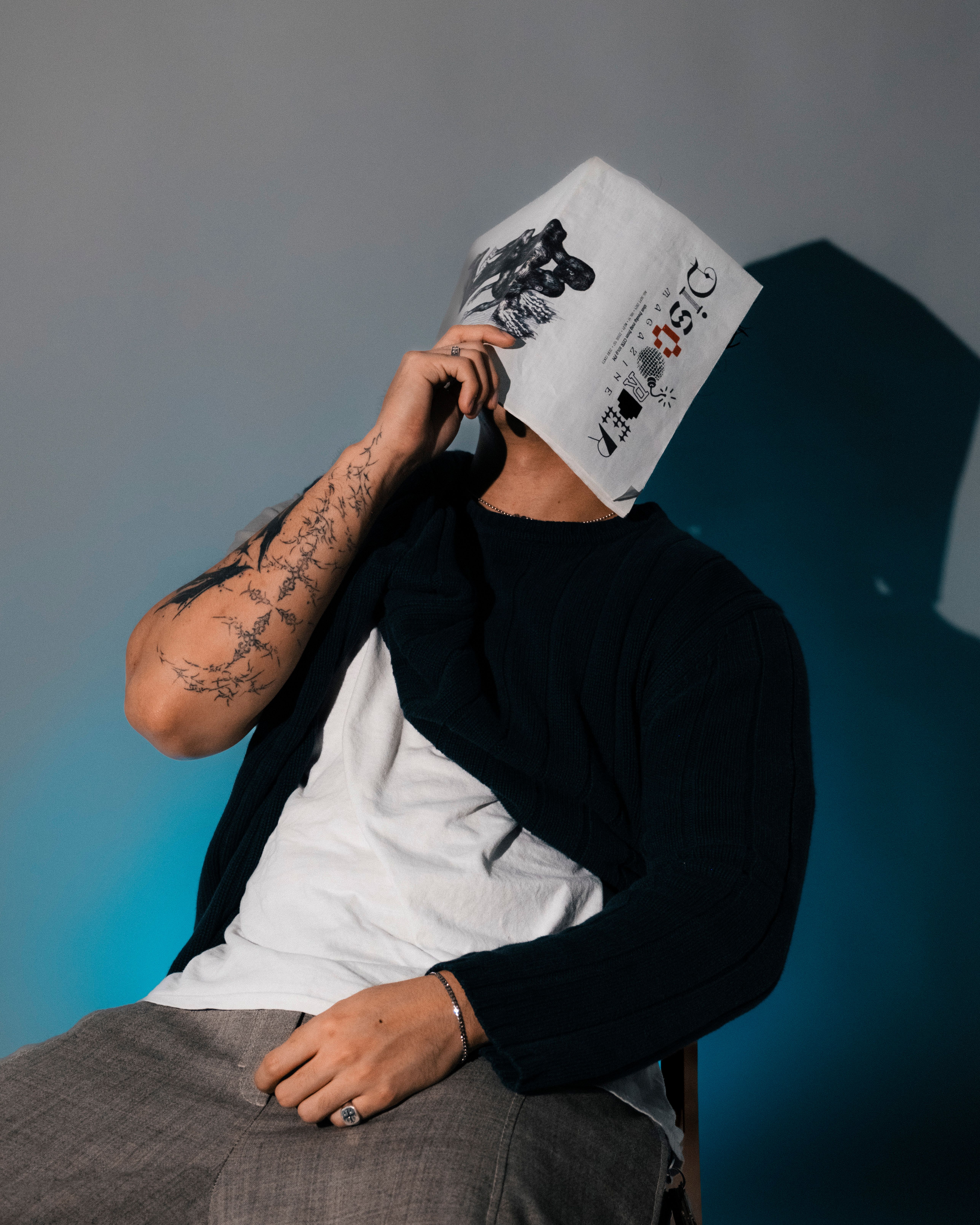 Artistic Tattooed Model Reading Newspaper in Studio · Free Stock Photo