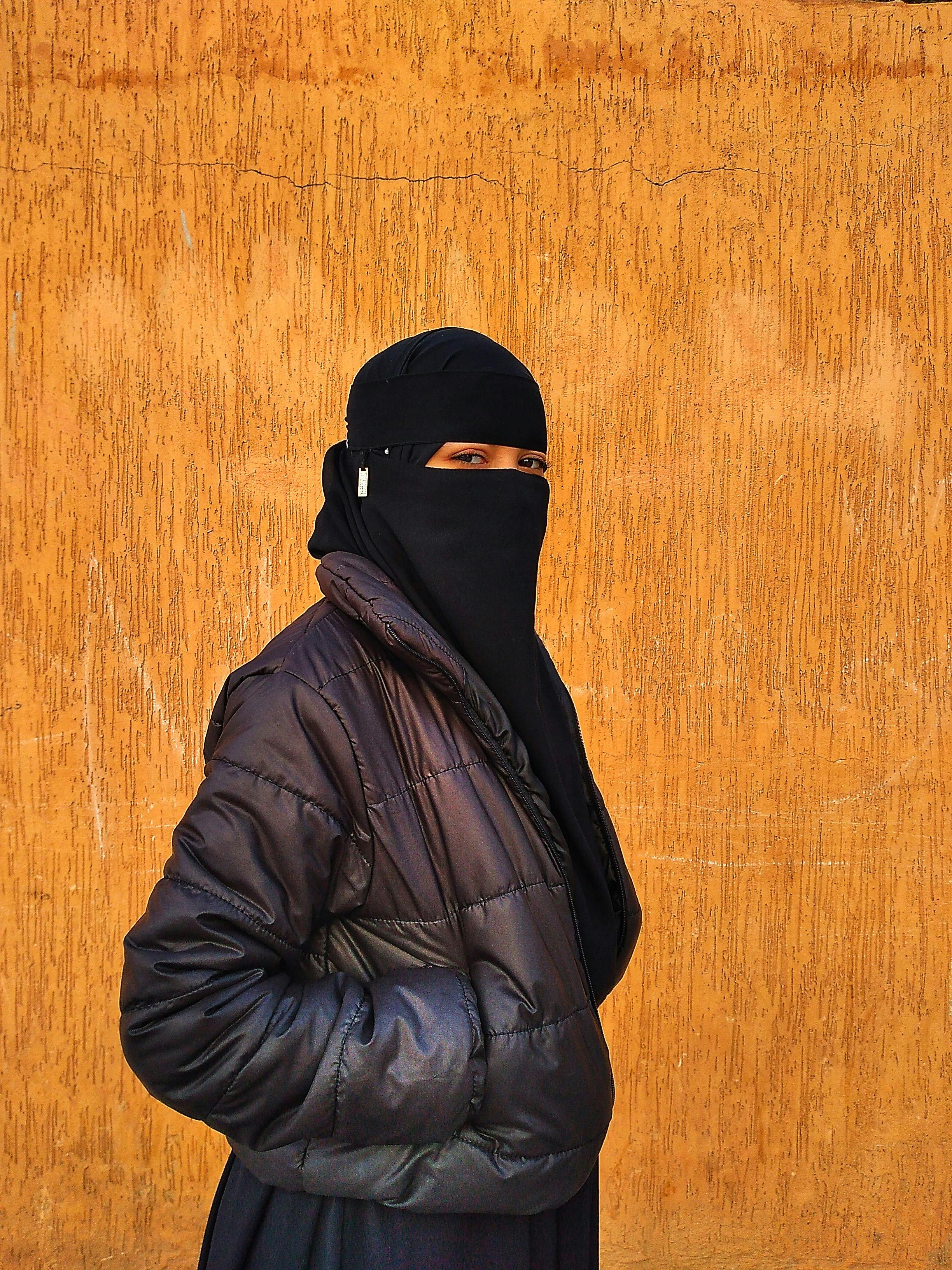 Potret Wanita Bercadar Hitam Di Dinding Oranye · Foto Stok Gratis