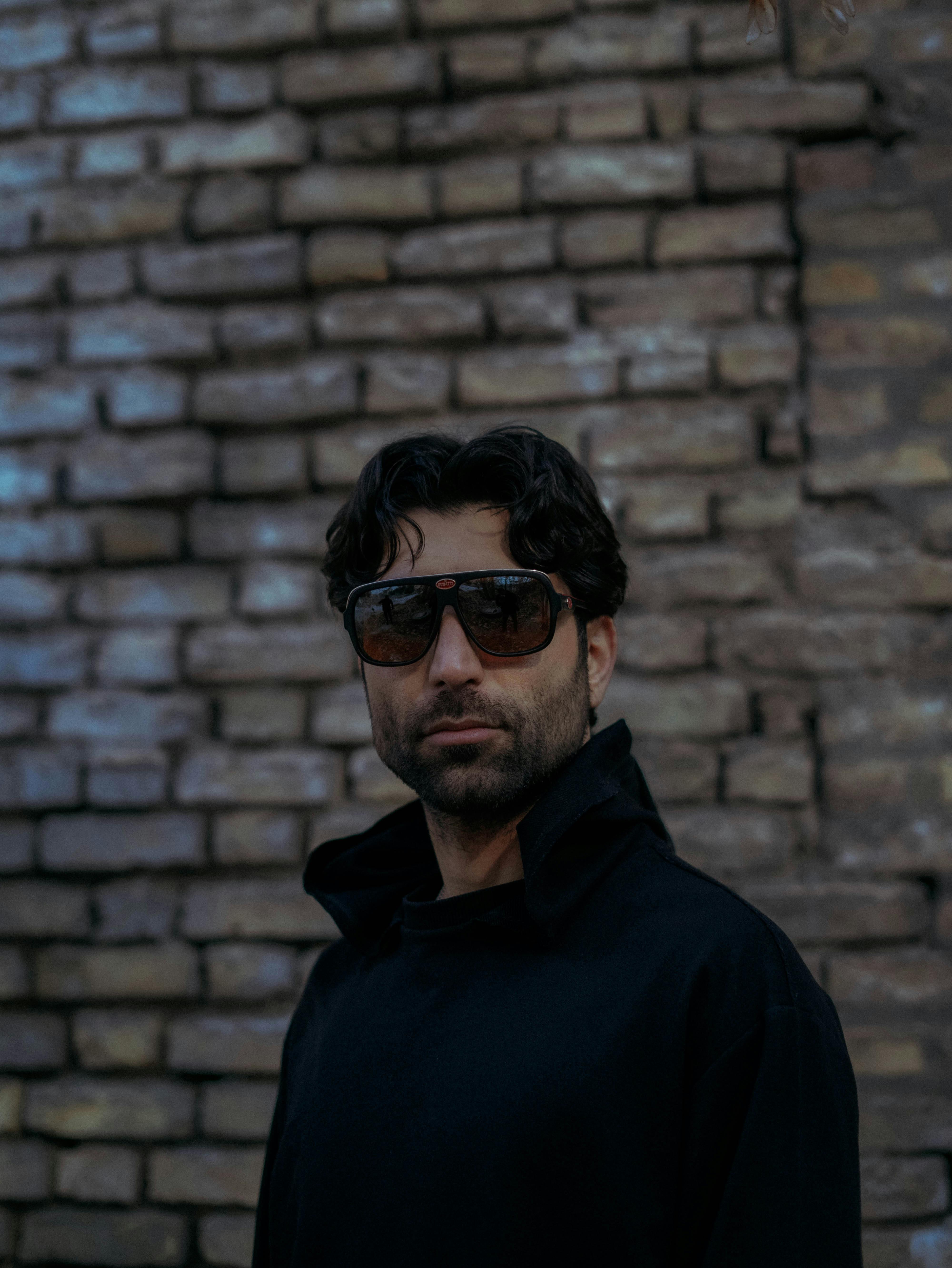 Man In Sunglasses Standing Against Brick Wall Free Stock Photo